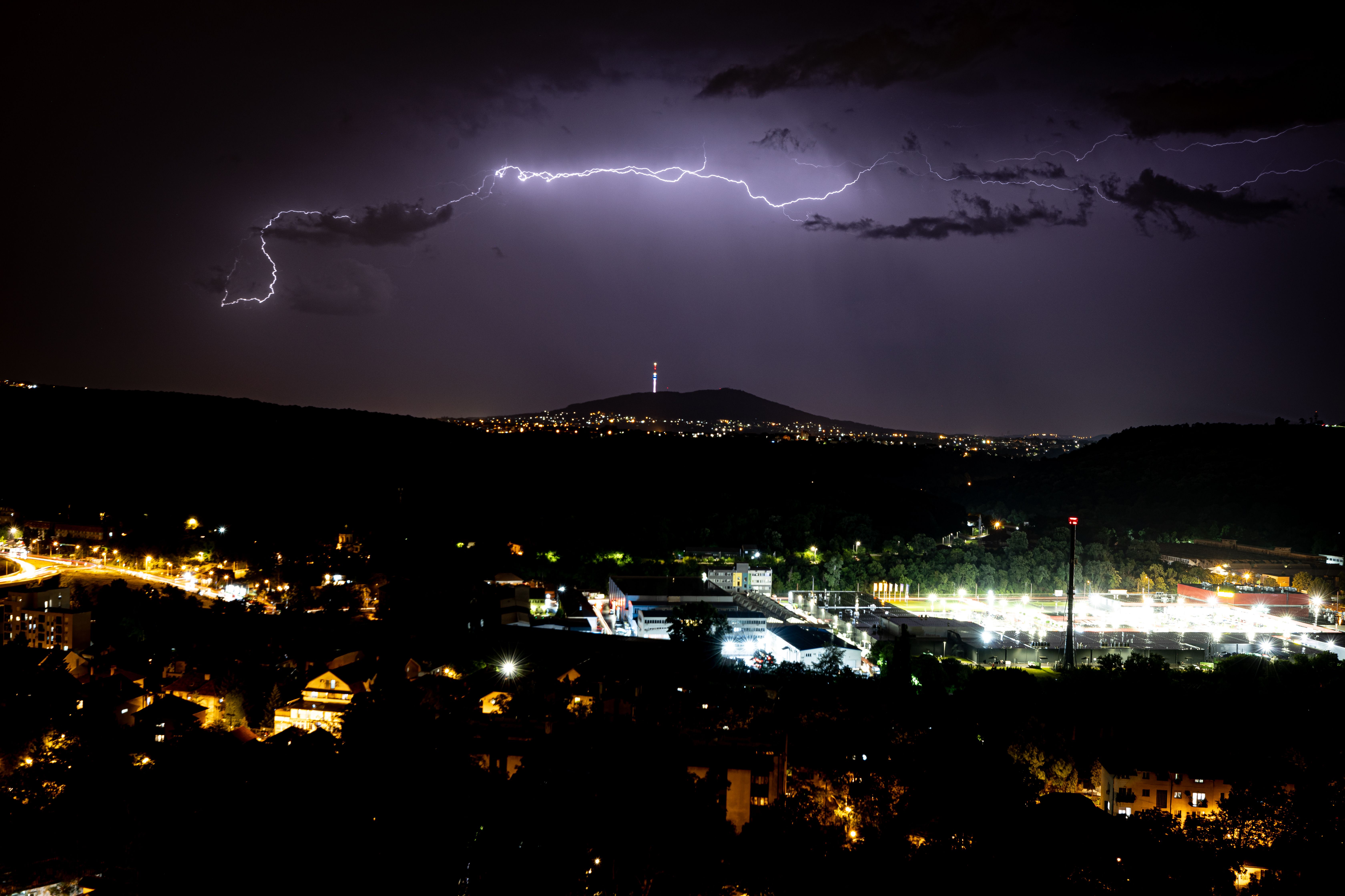 A lightning bolt is seen over a city at night · Free Stock Photo