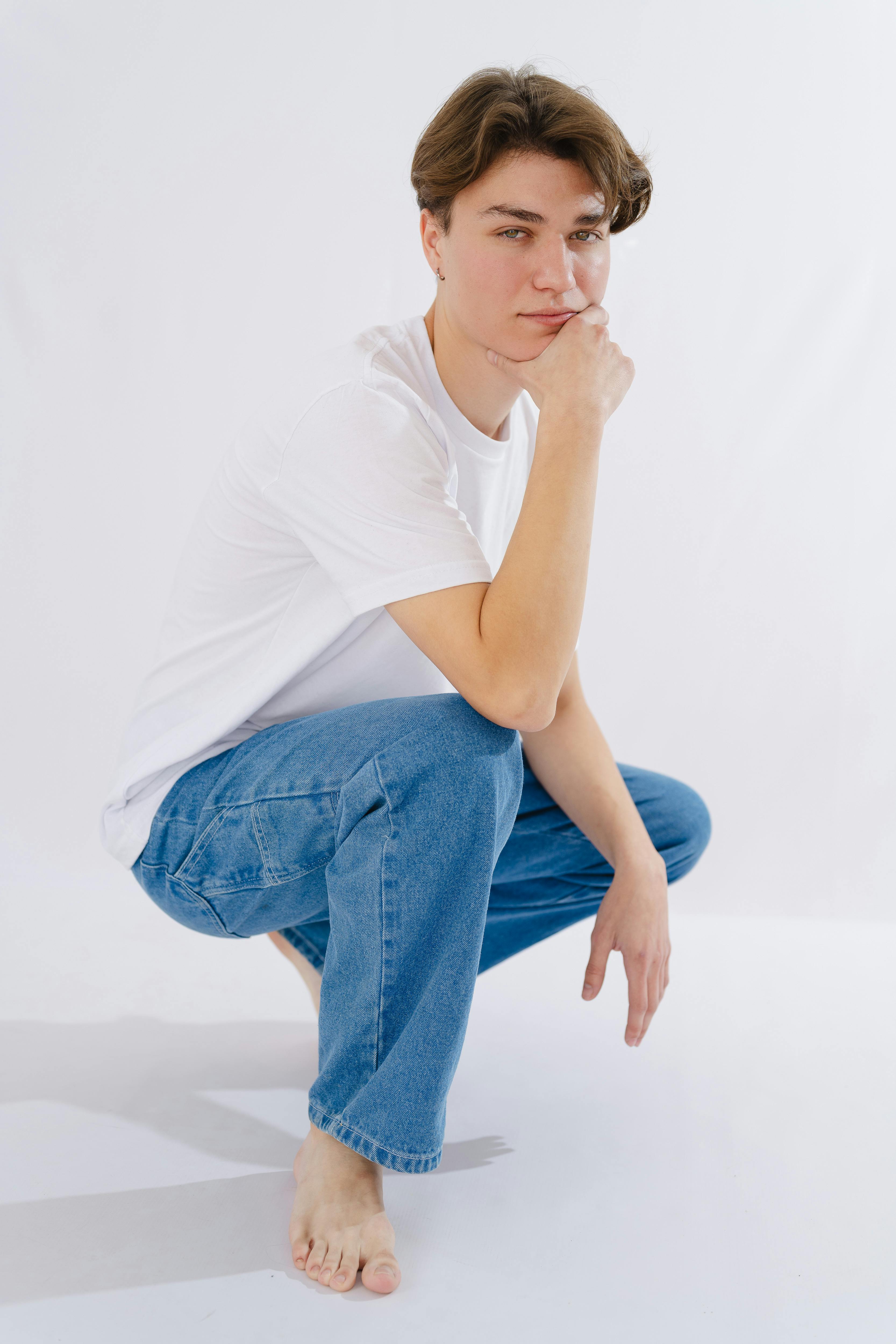 Young Model Crouching in Jeans · Free Stock Photo