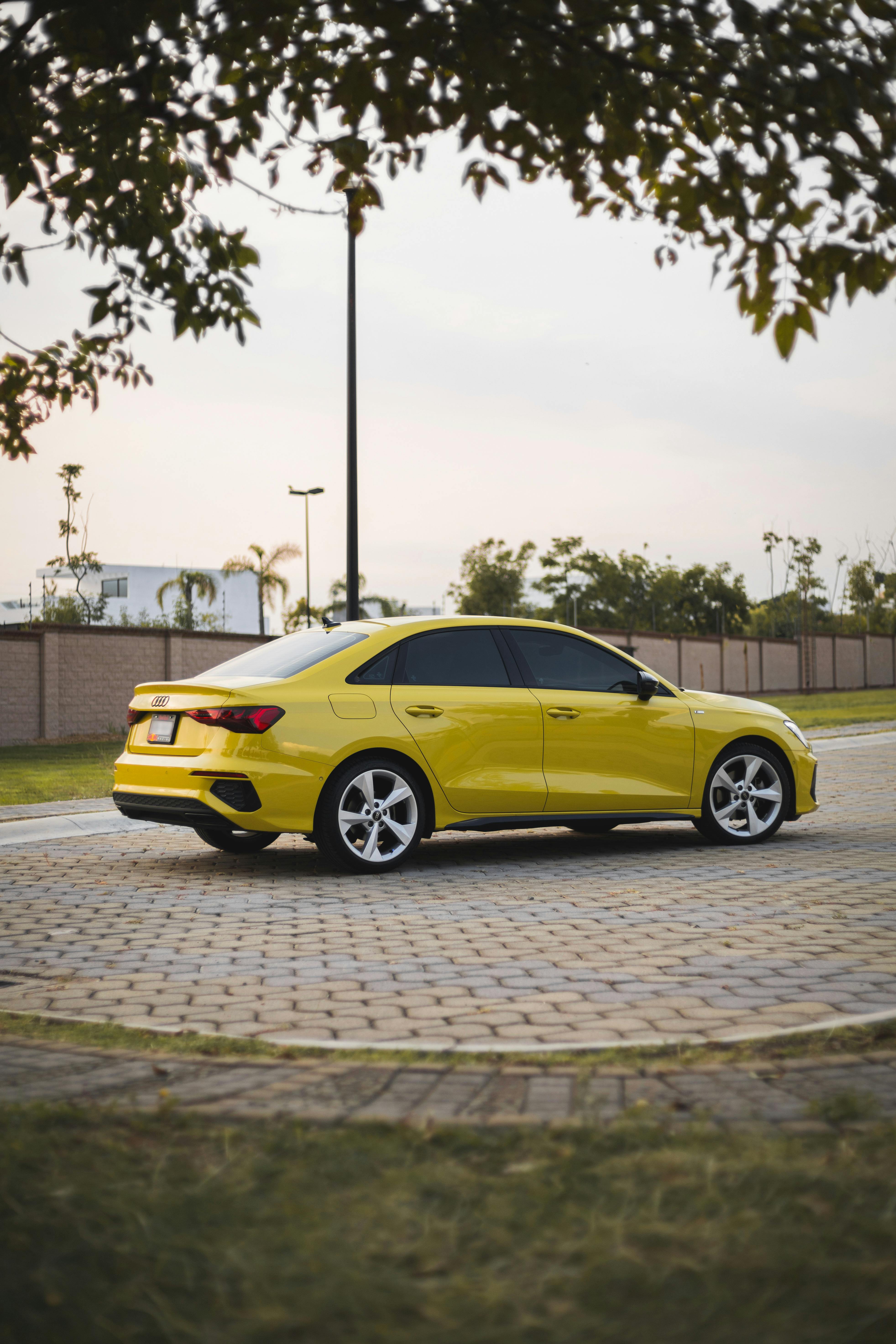 A yellow audi sedan parked on a brick road · Free Stock Photo