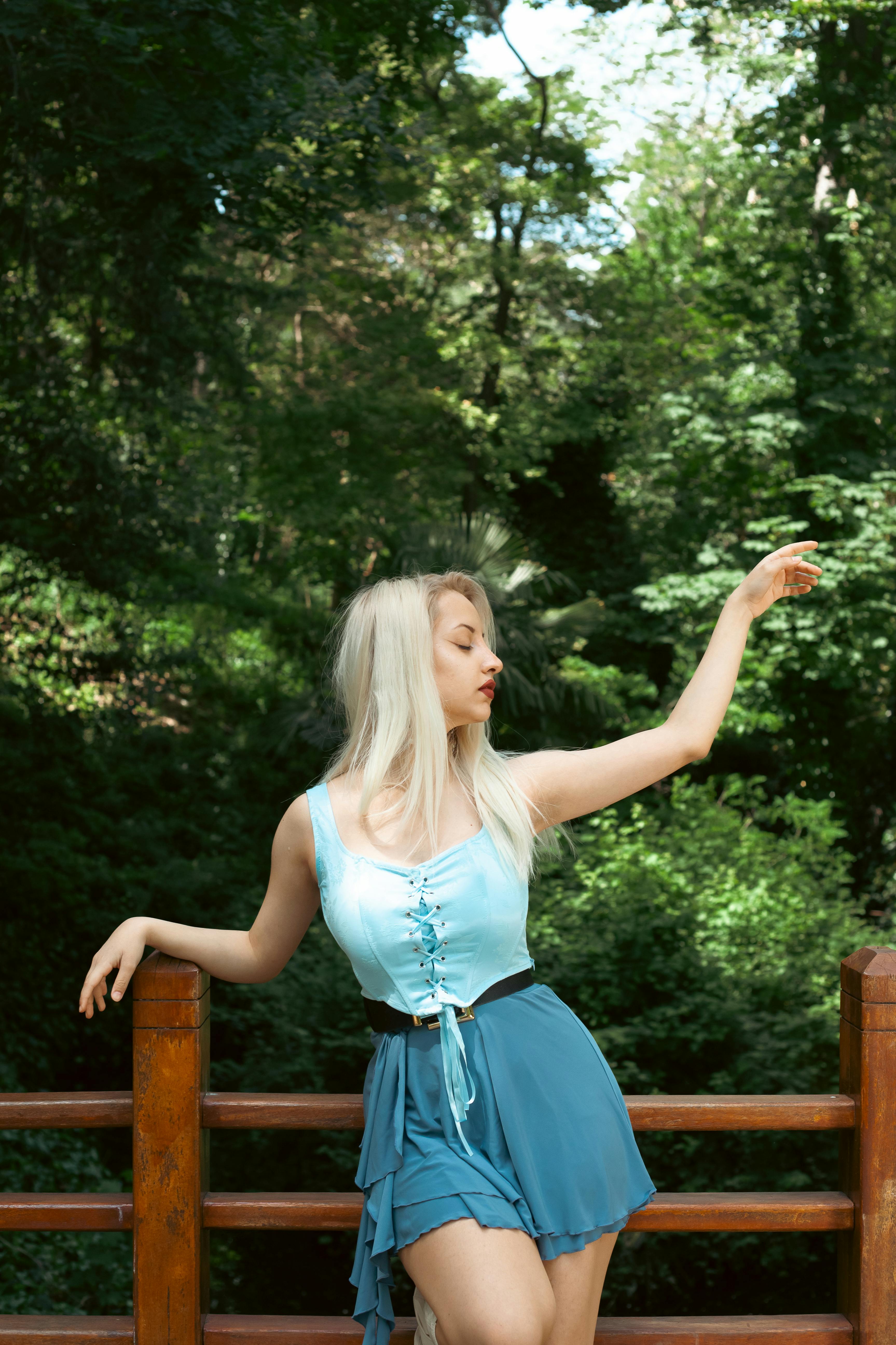 Blonde Woman Posing in Park Wearing Light Blue Top and Dark Blue Skirt ...
