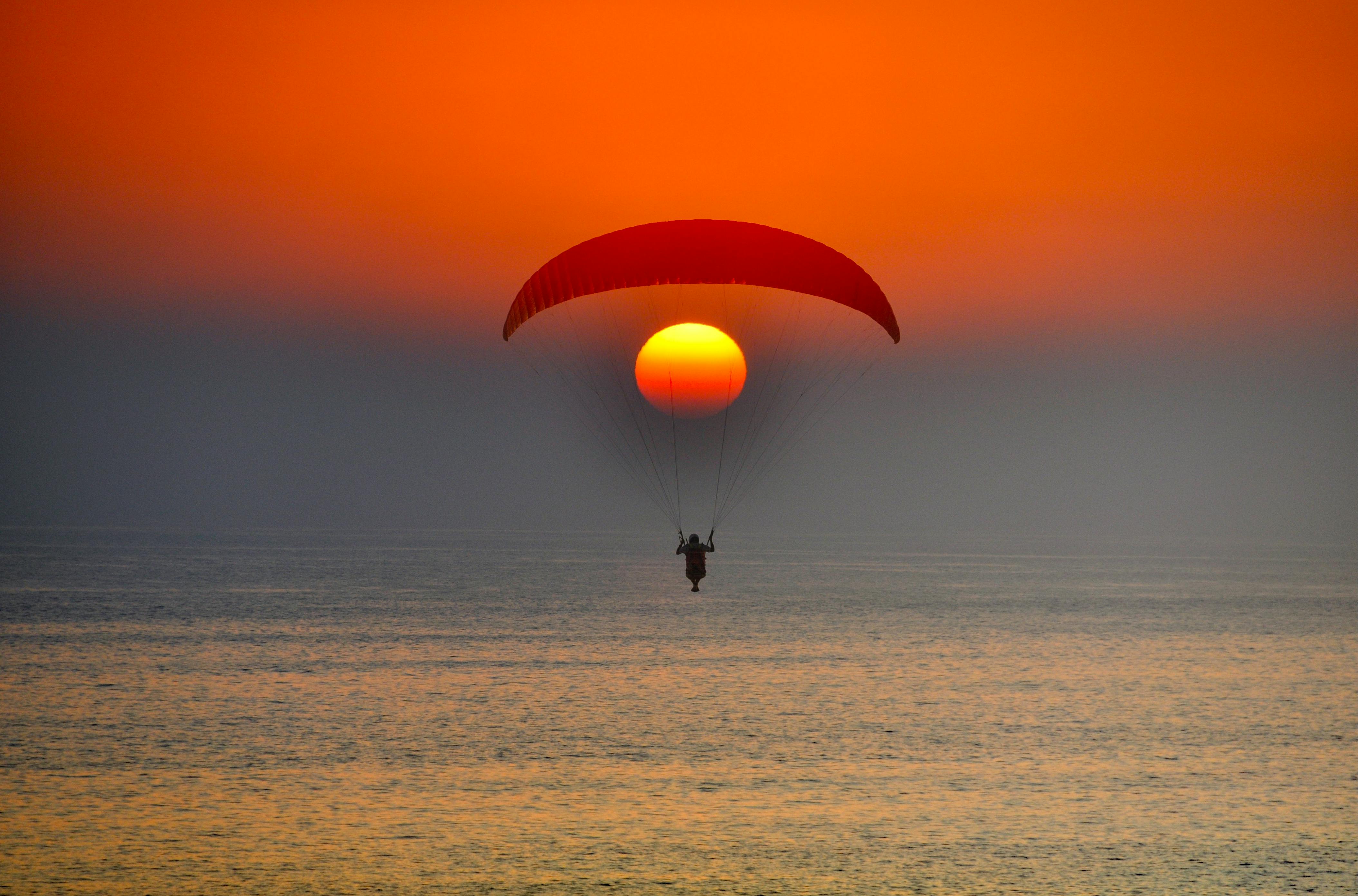 Person with Parachute over Sea at Sunset · Free Stock Photo