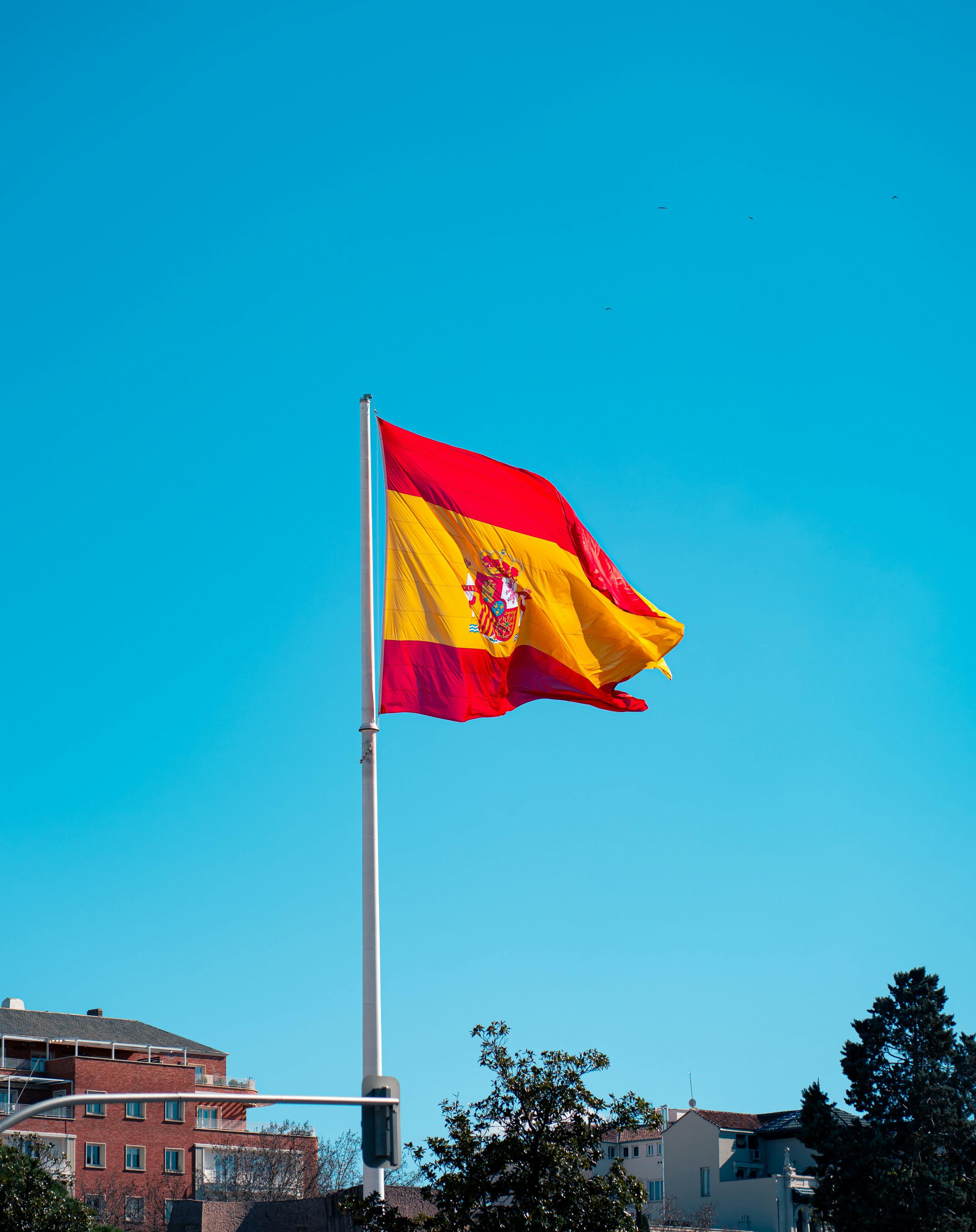 Spanish Flag Over the City by the Blue Sky · Free Stock Photo
