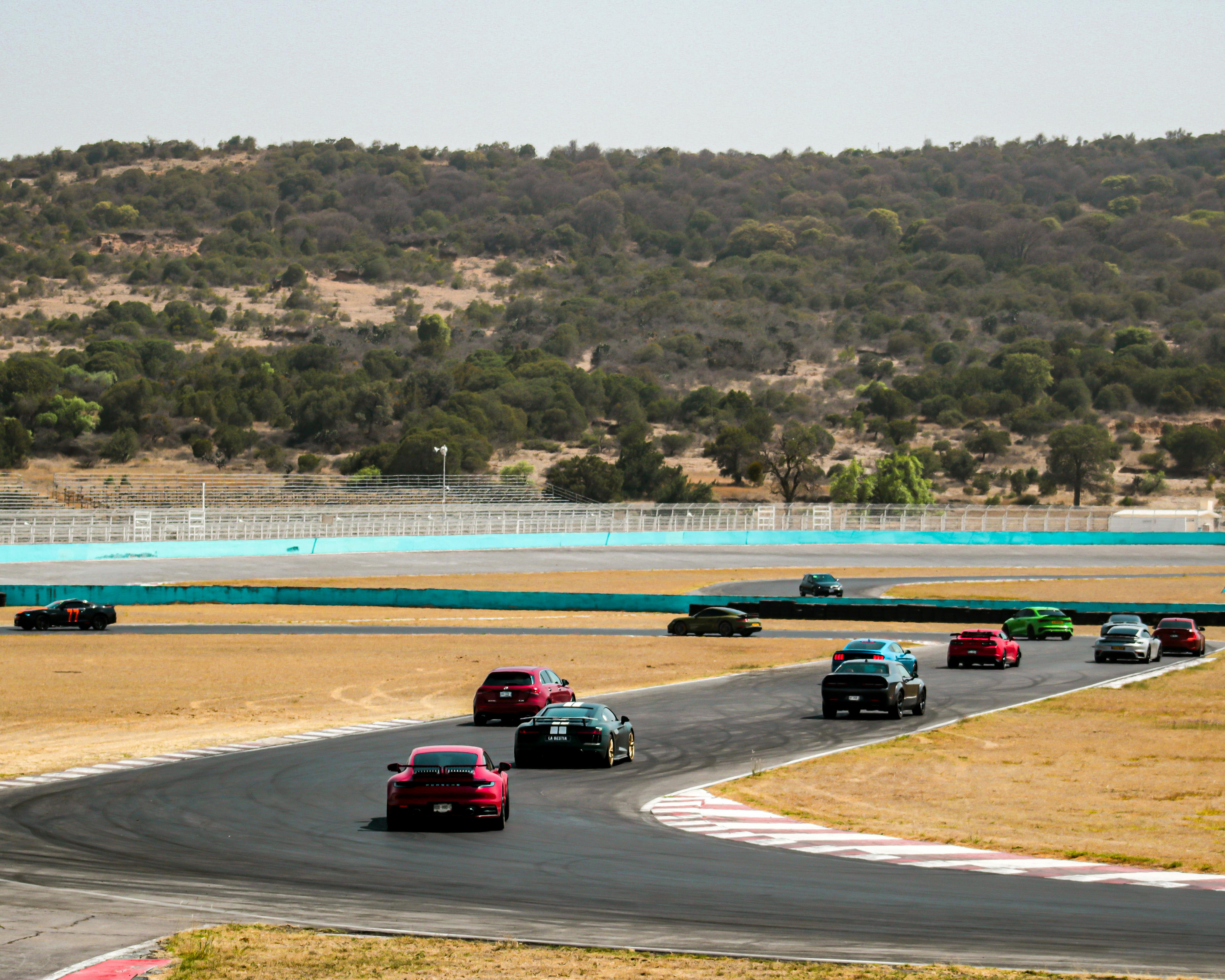 A group of cars driving on a race track · Free Stock Photo