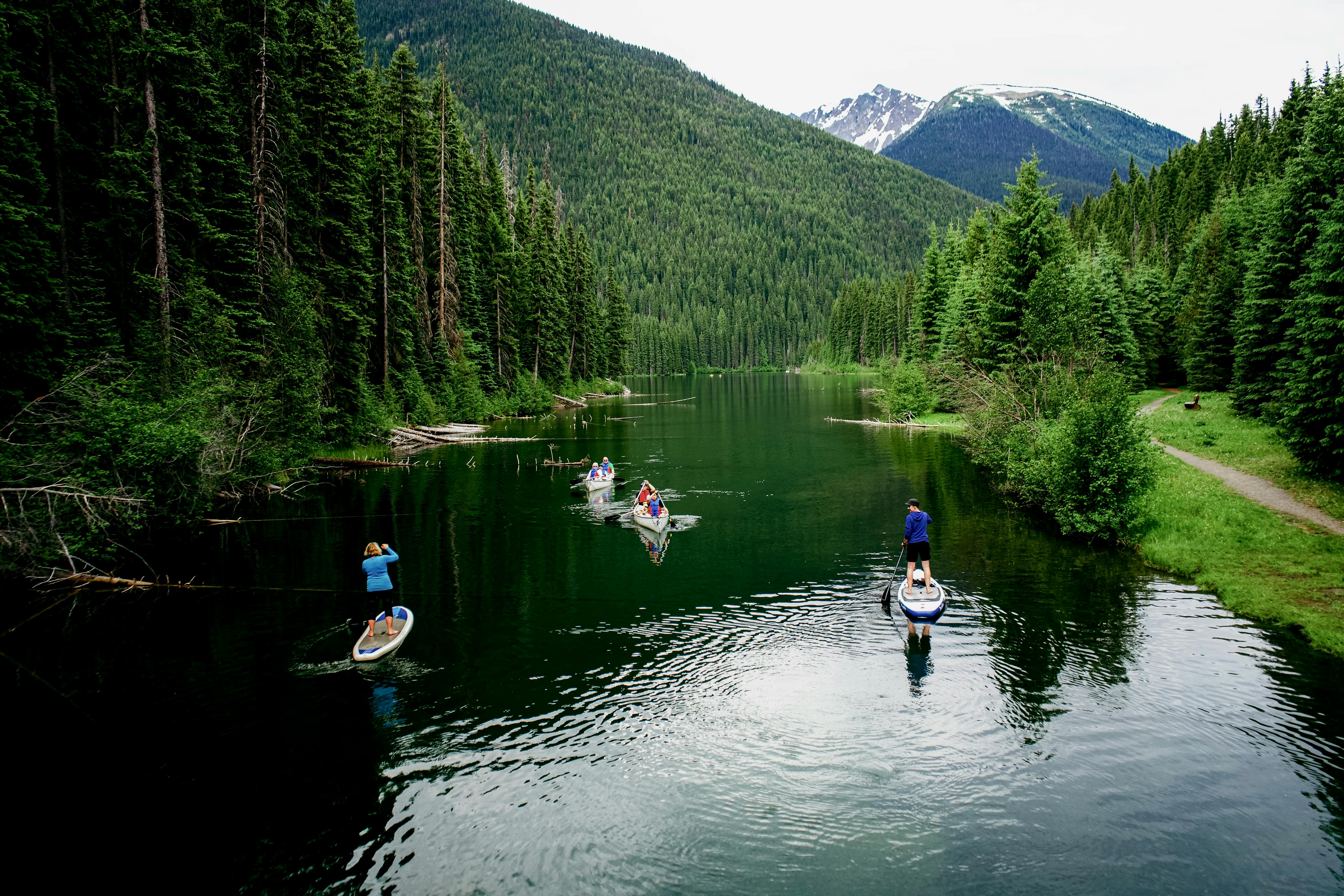 People on Boats and Paddle Boards on River in Mountains · Free Stock Photo