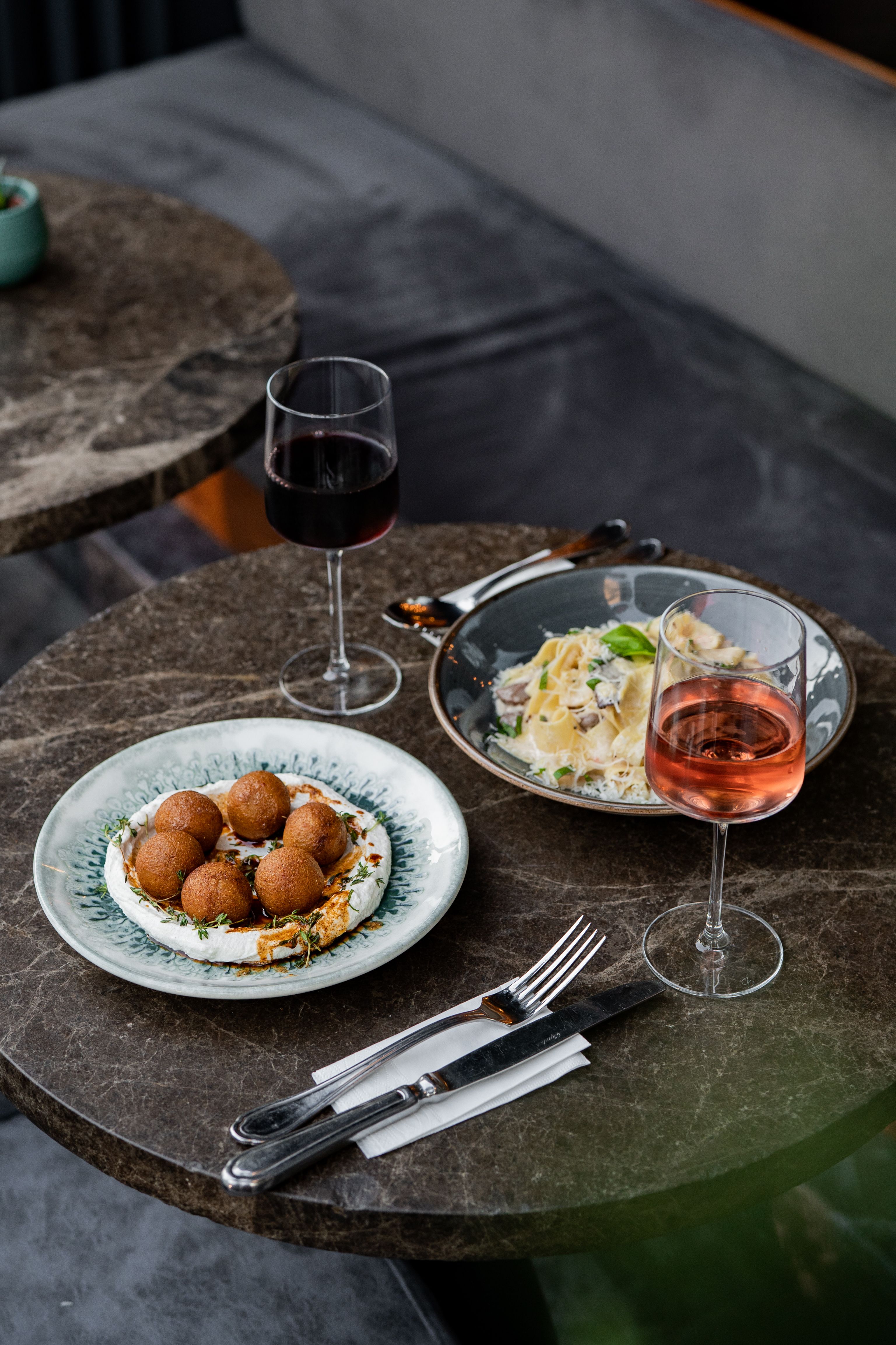 Two plates of food sit on a table with wine glasses · Free Stock Photo