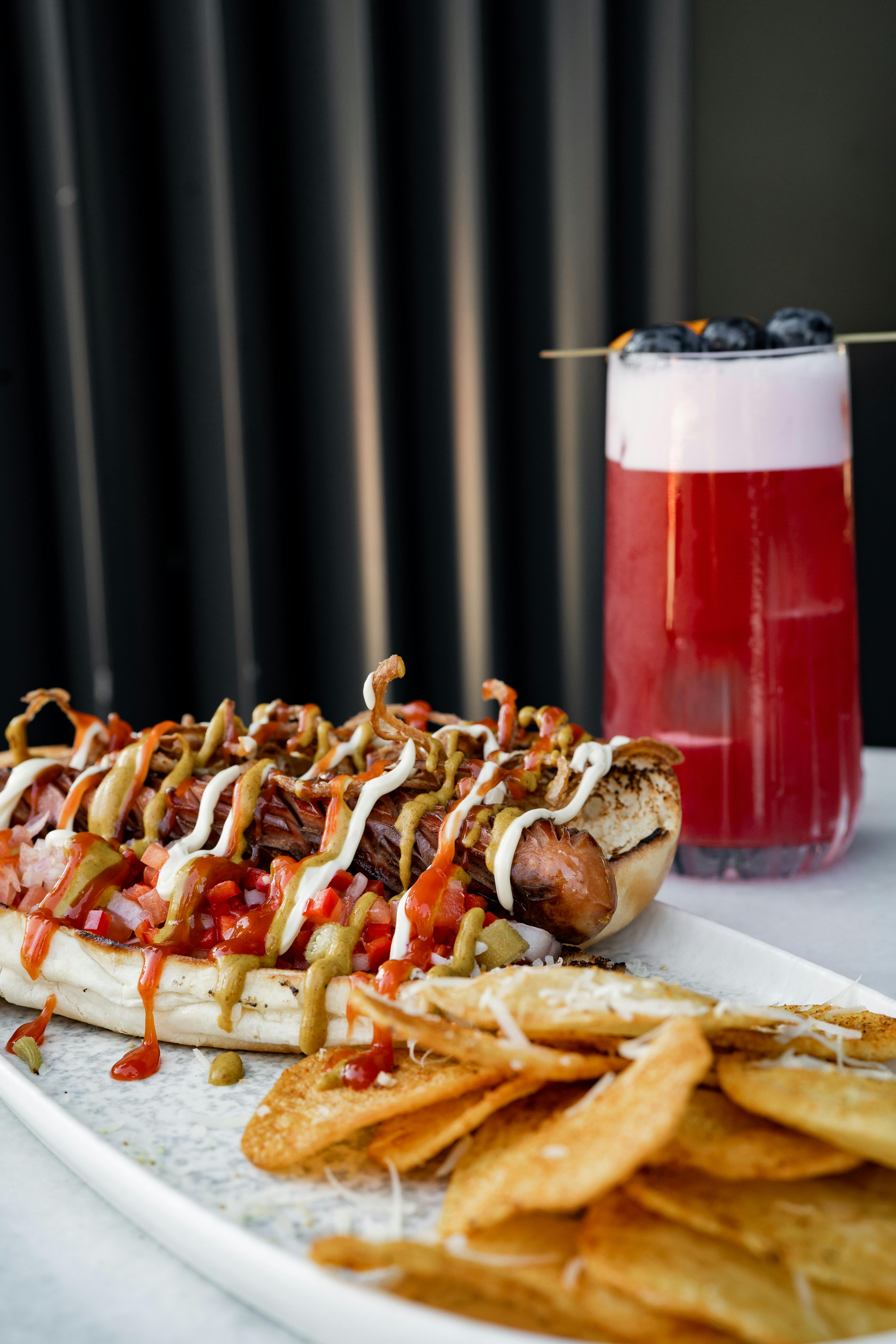 A hot dog with chips and a drink on a plate · Free Stock Photo