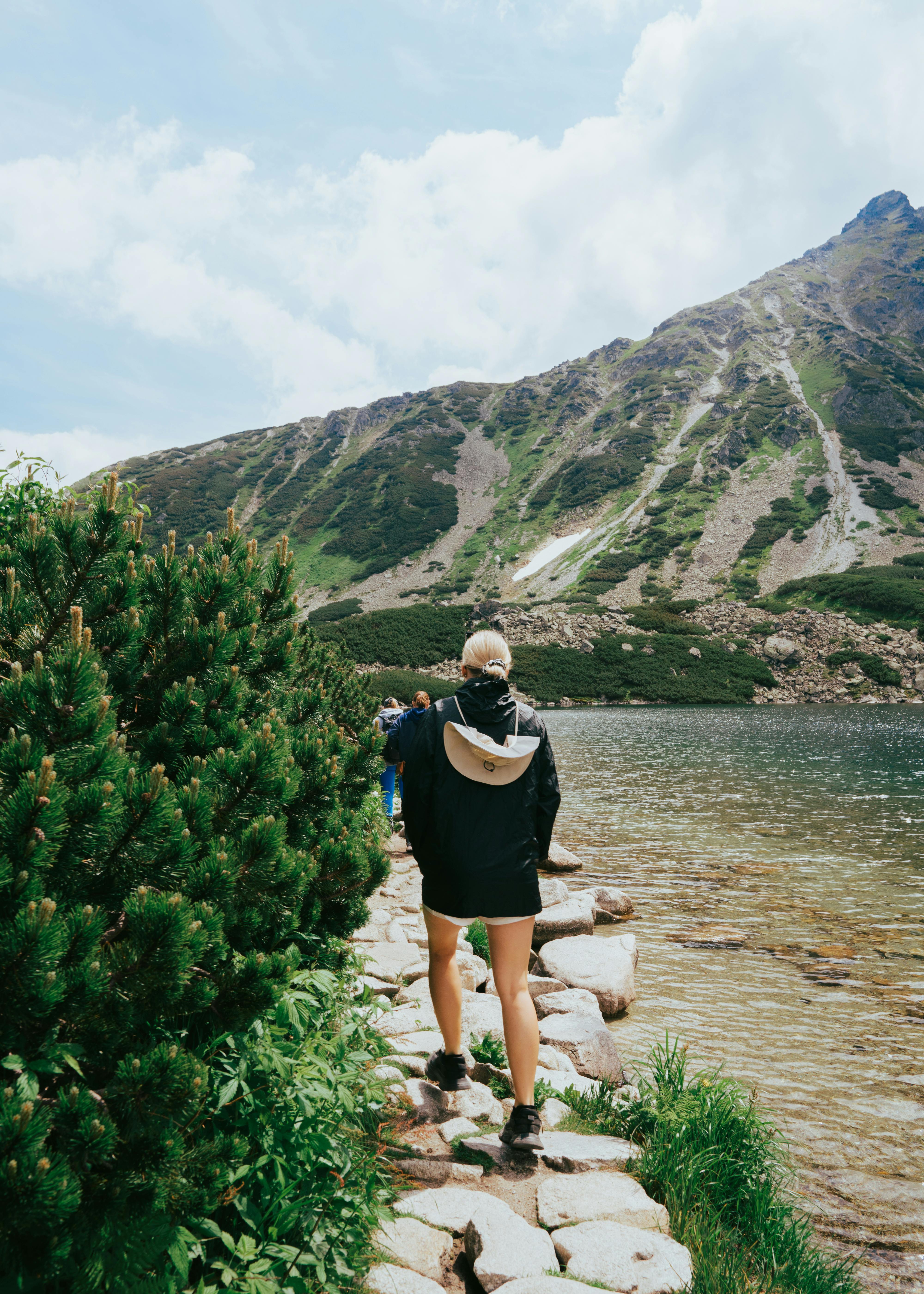 Back View of Woman Walking on Stone Trail near Lake in Mountains · Free ...