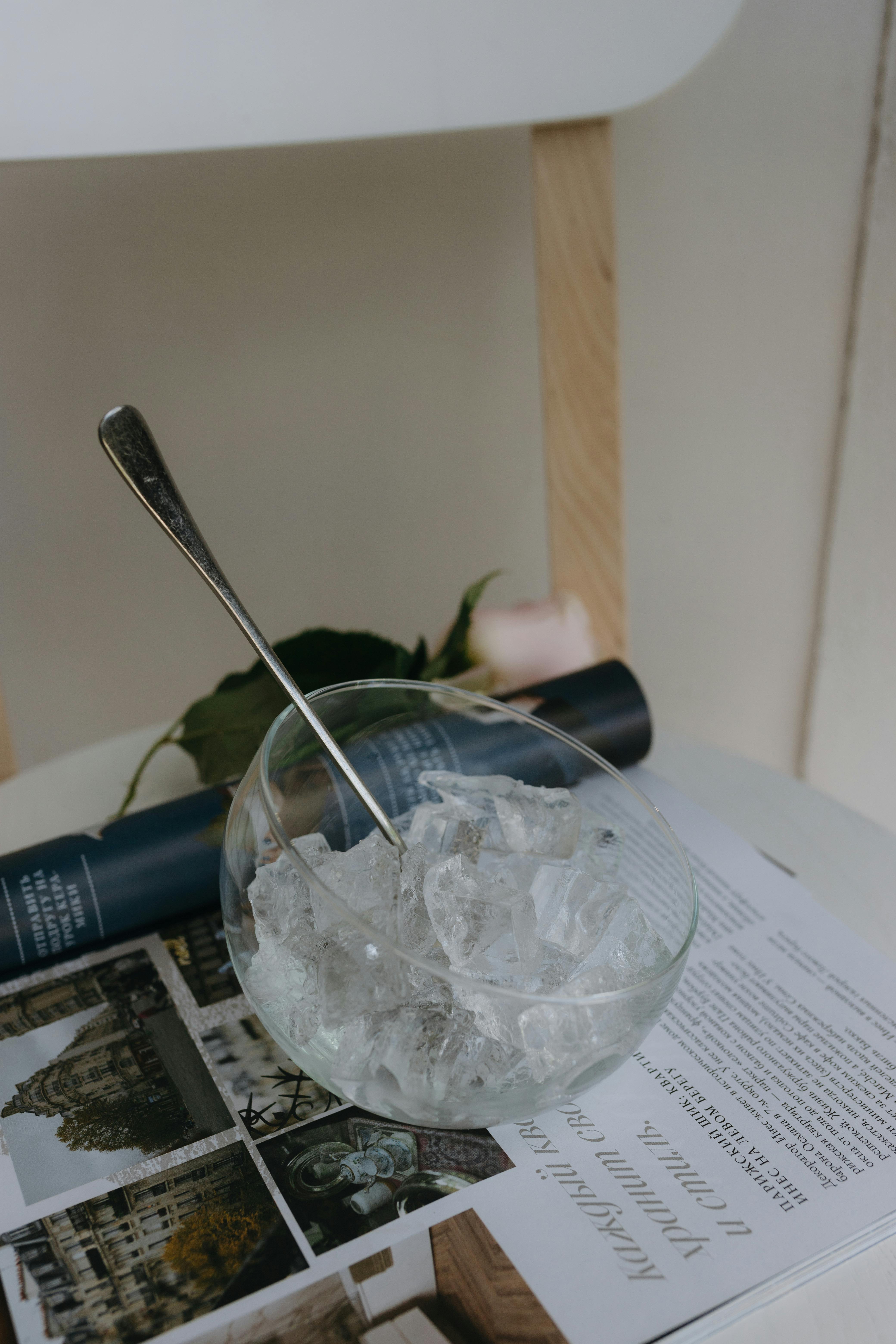 A glass bowl with ice and a spoon on top of a magazine · Free Stock Photo