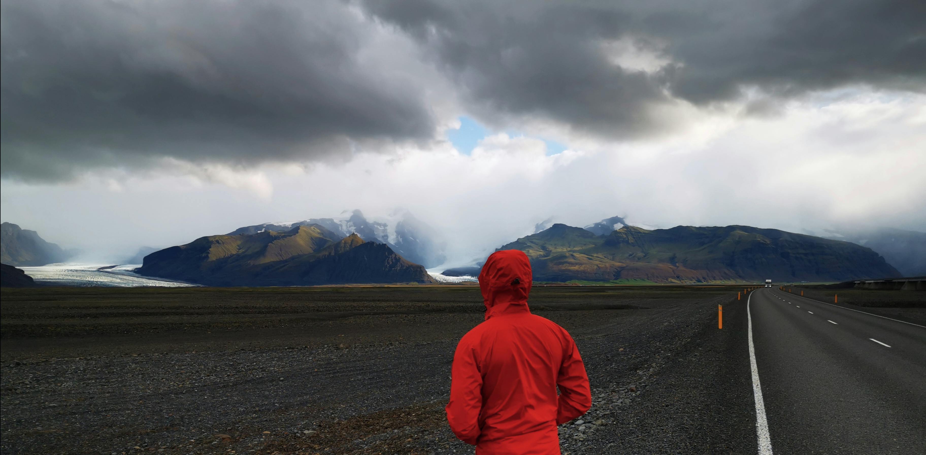 Person in Red Jacket Standing near Road on Wasteland in Iceland · Free ...