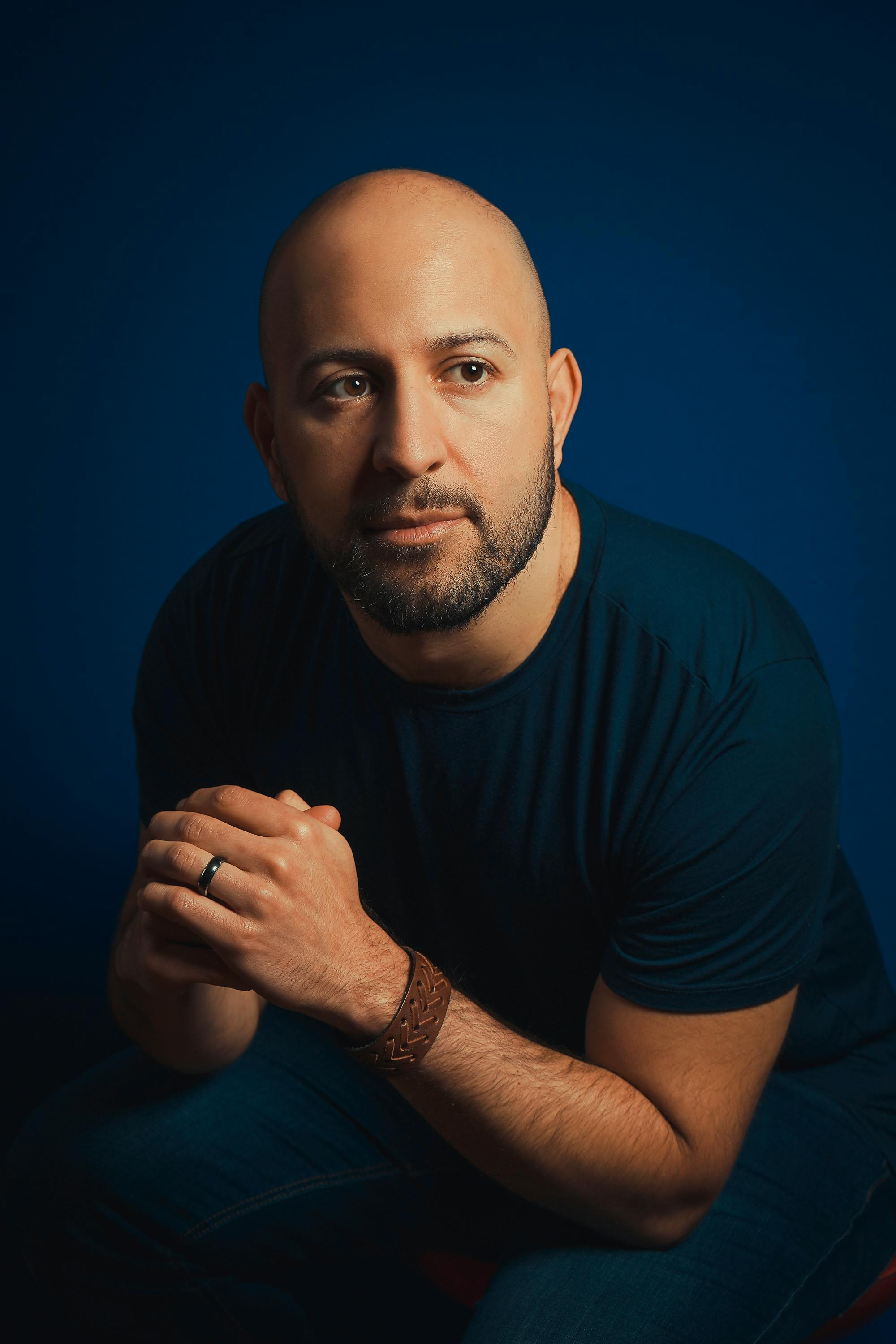 Portrait of a Bald Man Posing against a Blue Wall · Free Stock Photo