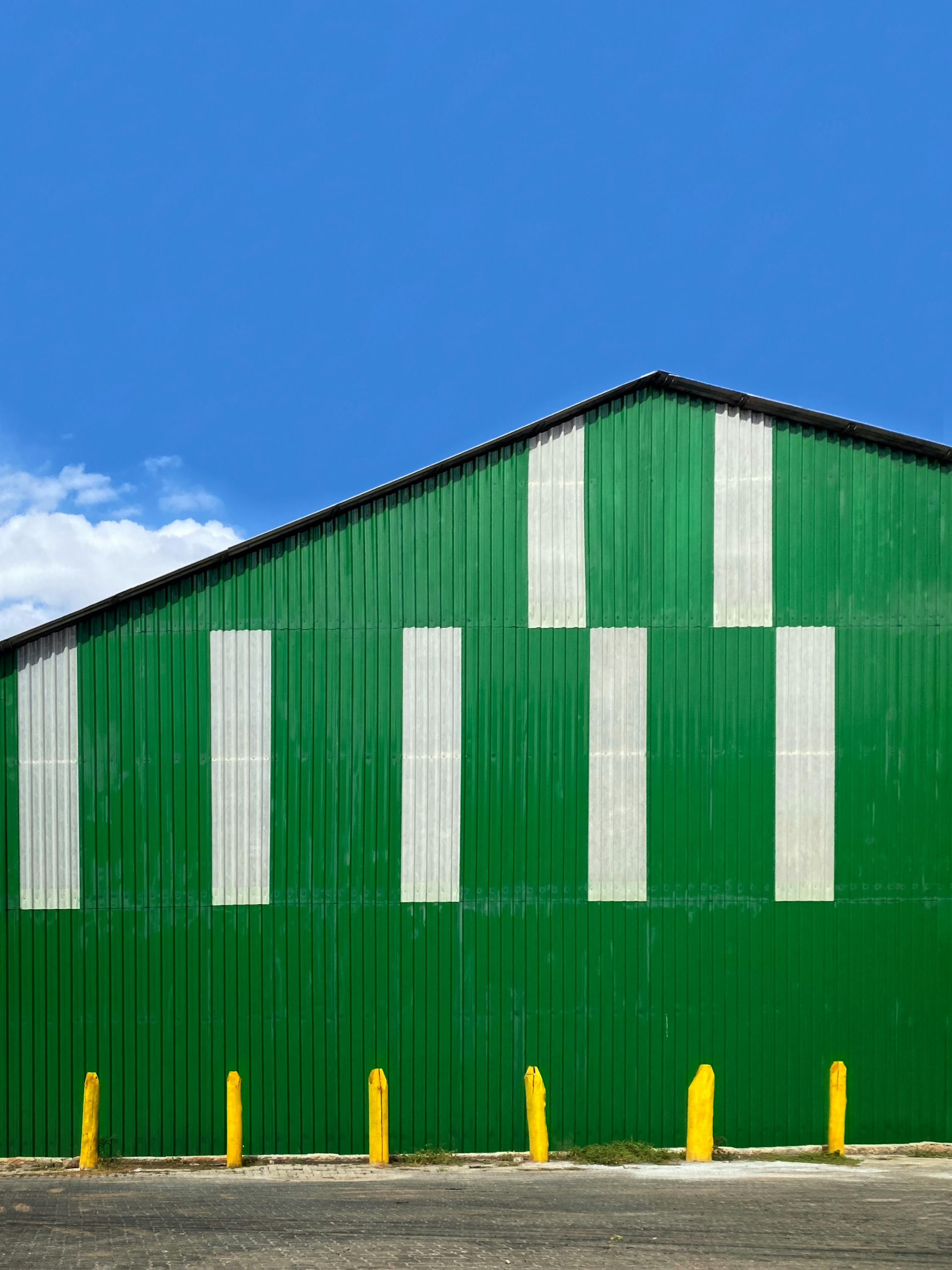 Green and White Industrial Building with Yellow Posts · Free Stock Photo