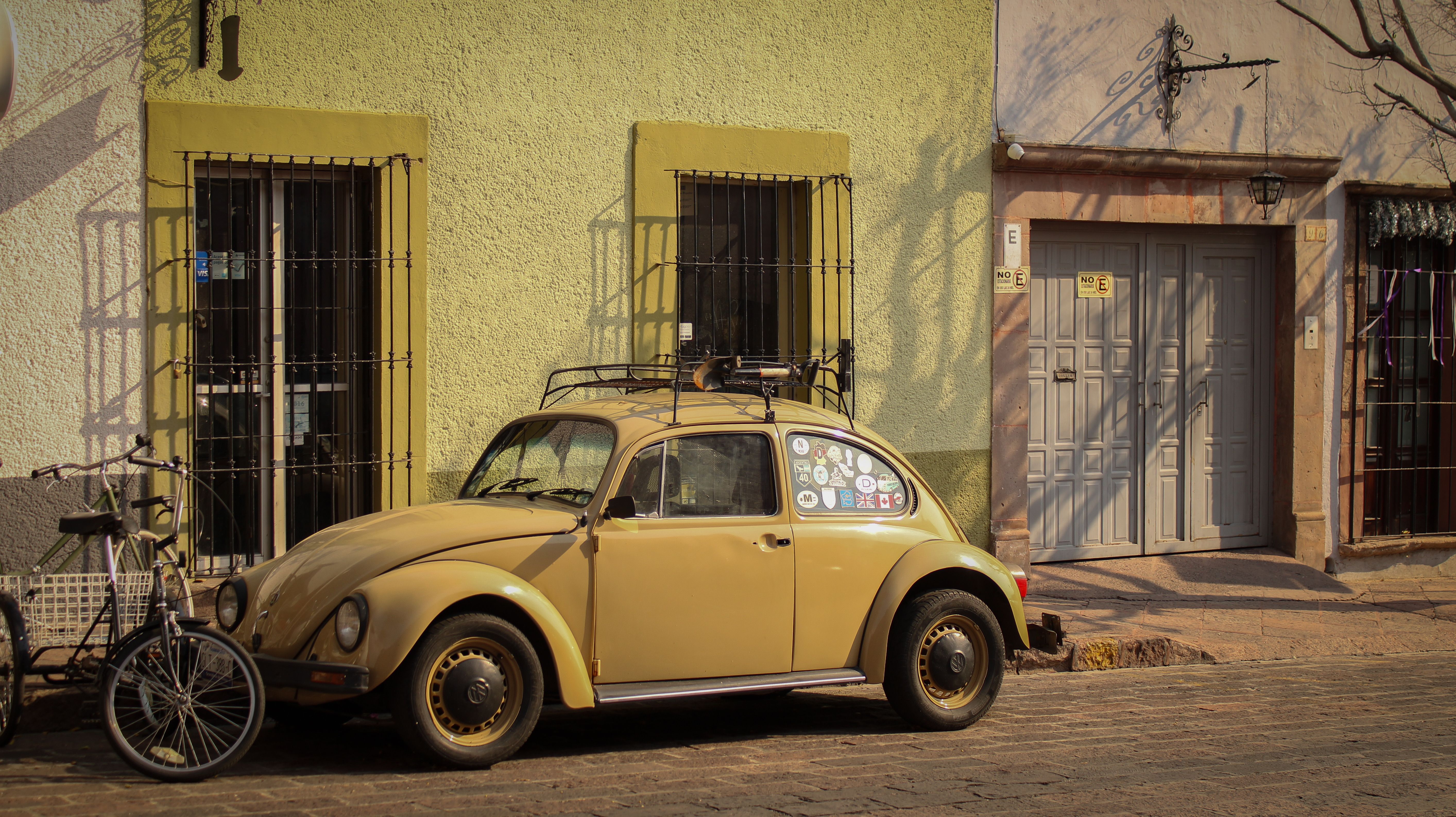 A yellow vw beetle parked in front of a building · Free Stock Photo