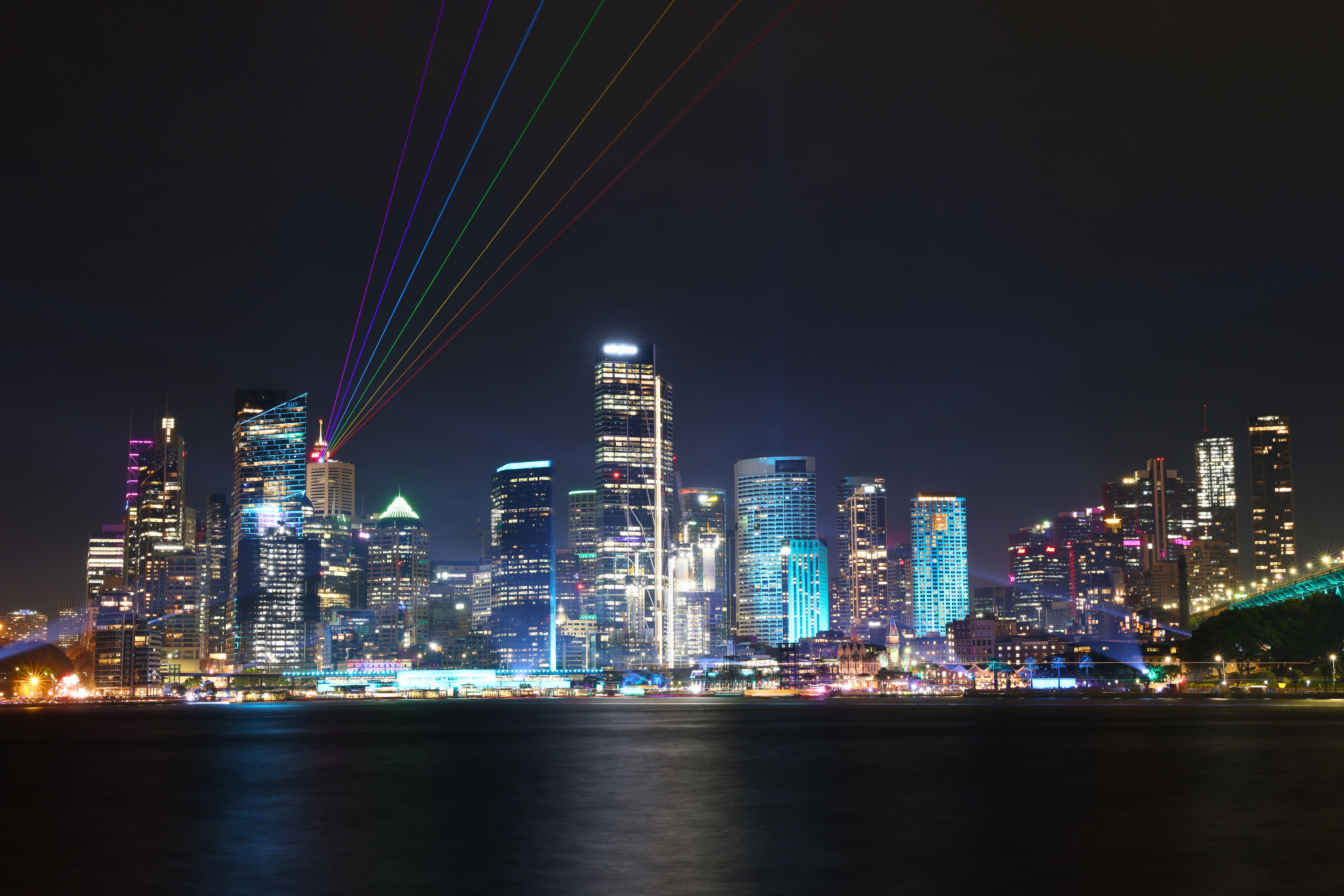 A city skyline with colorful lights and a rainbow · Free Stock Photo