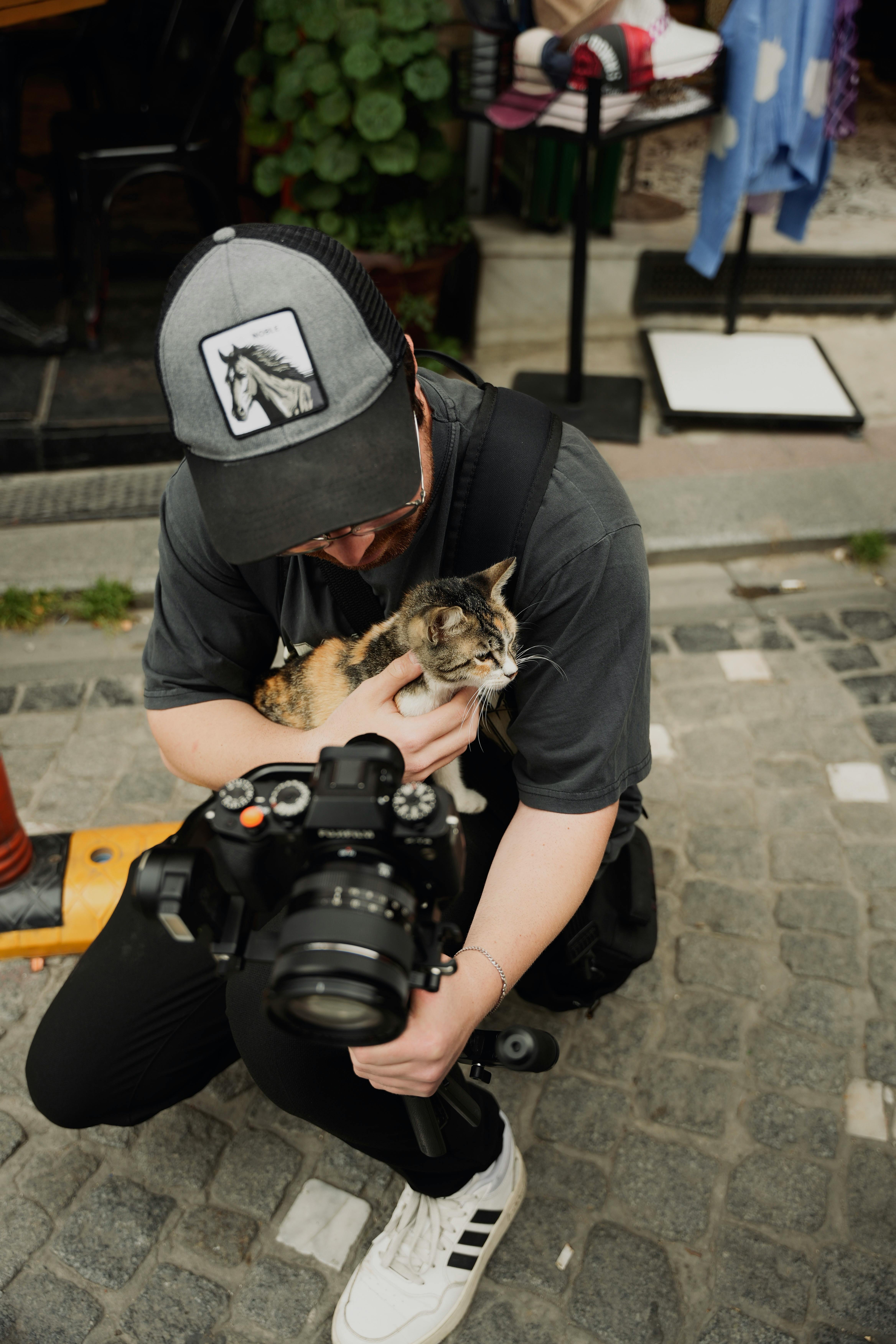 Man with Camera Holding Kitten on Street · Free Stock Photo