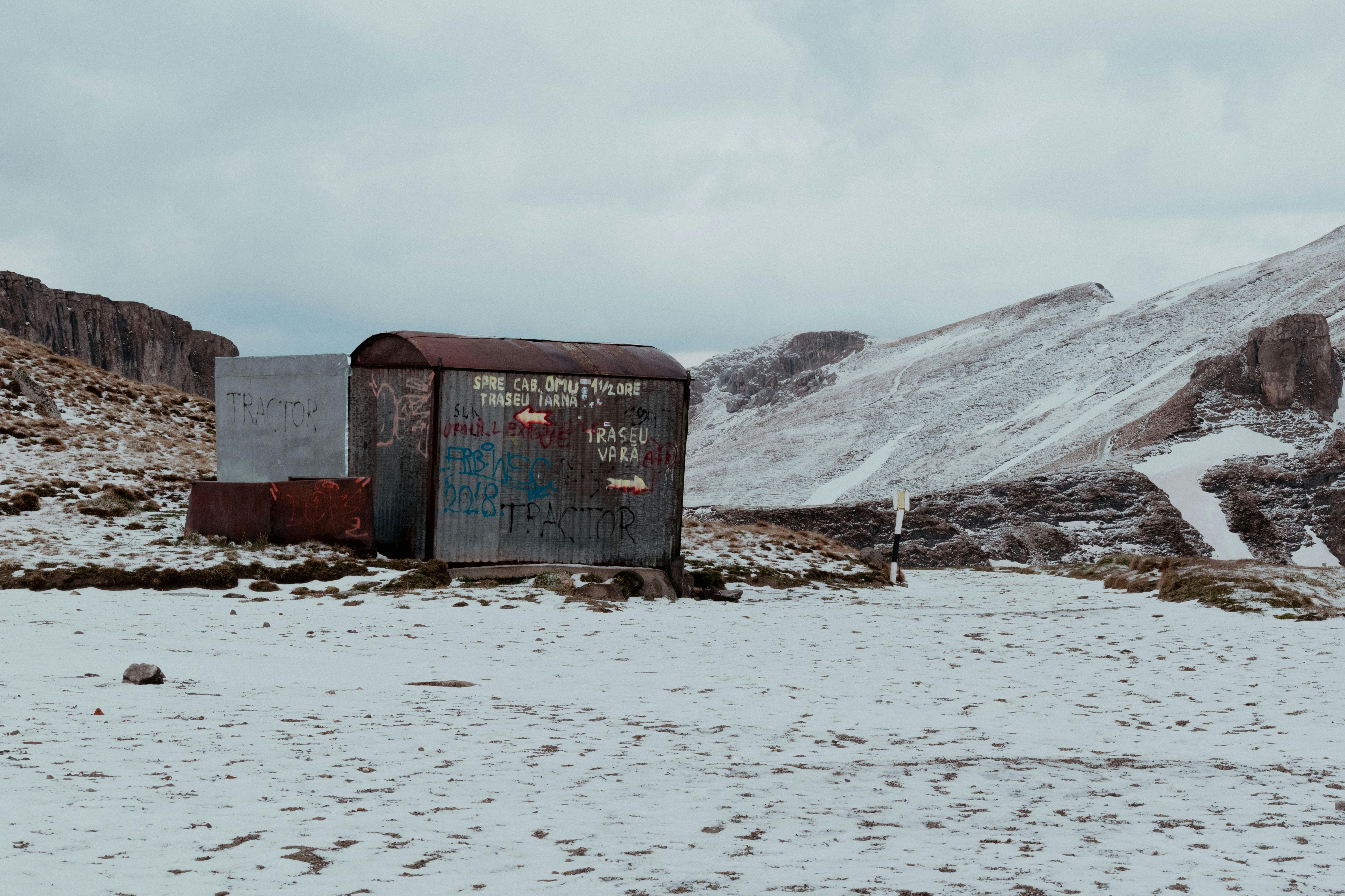 A small shack in the snow with mountains in the background · Free Stock ...