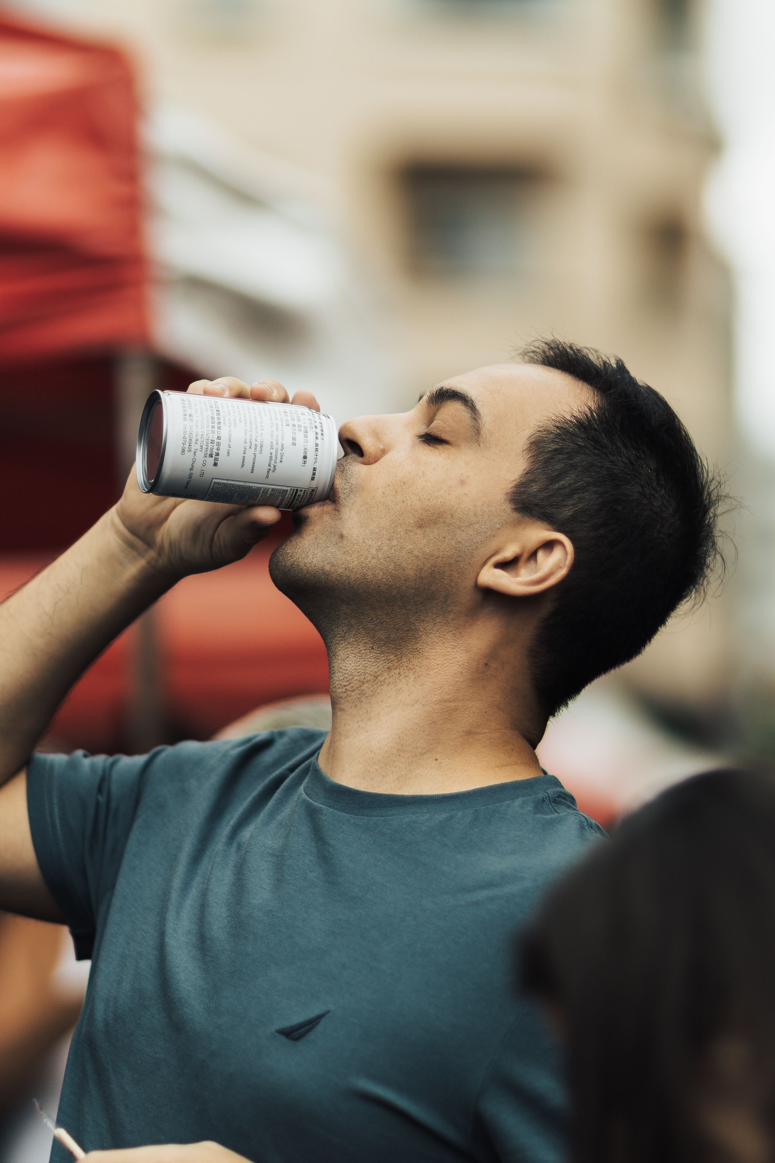 Side View of a Man Drinking from a Can on a Street · Free Stock Photo