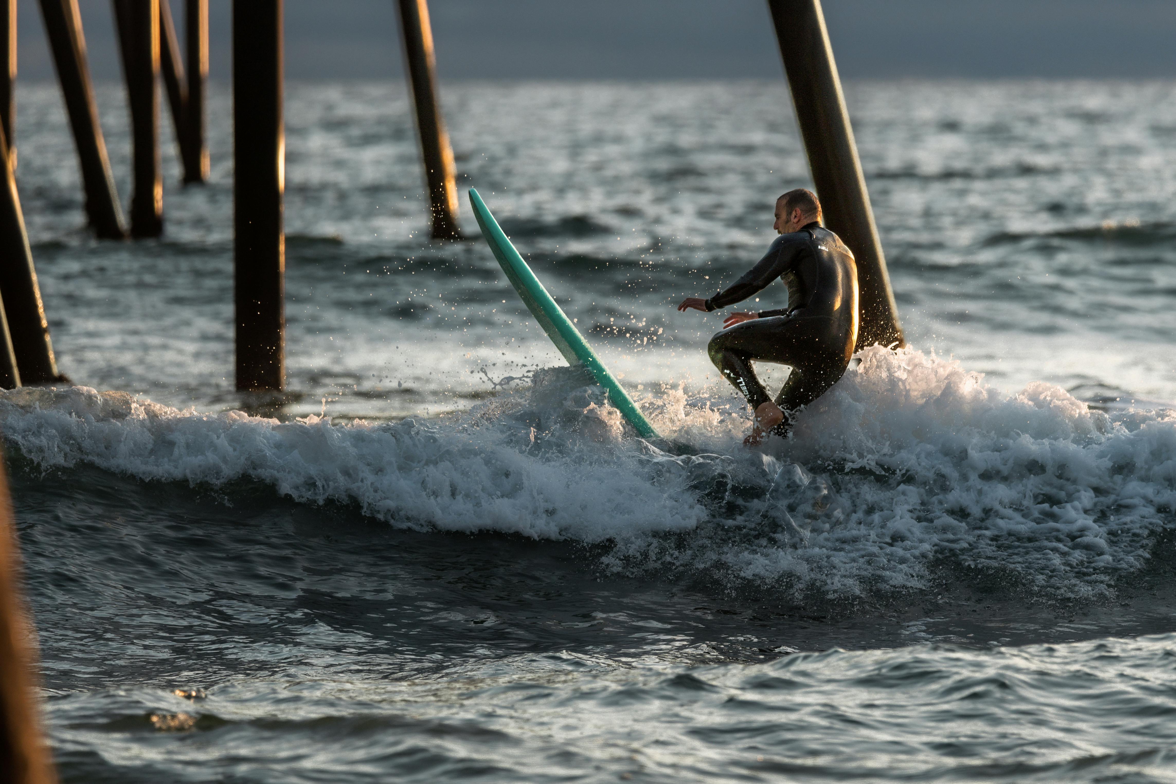 Man Surfing under a Pier · Free Stock Photo