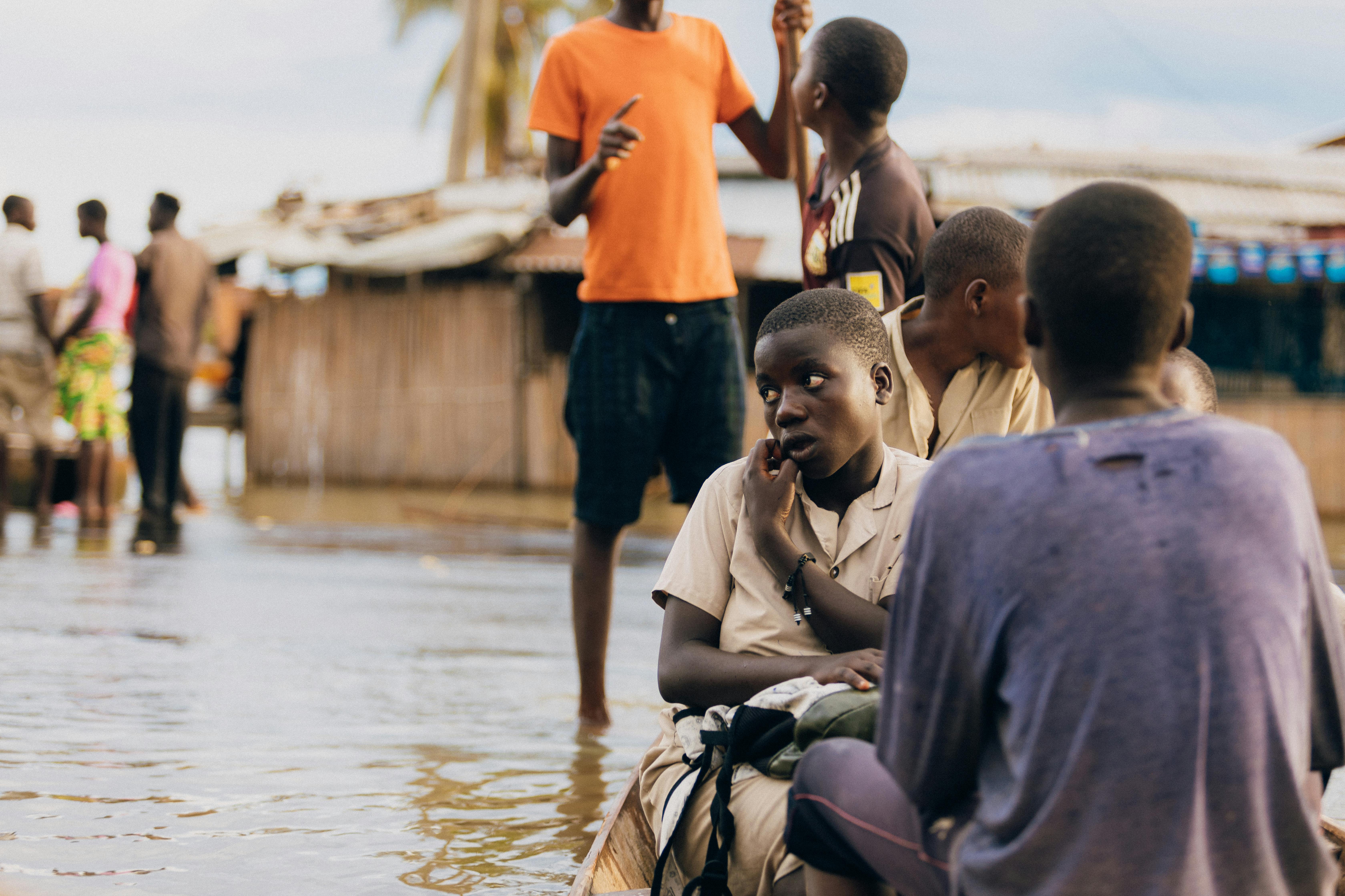 Boys Sitting on Boat in Village during Flood · Free Stock Photo