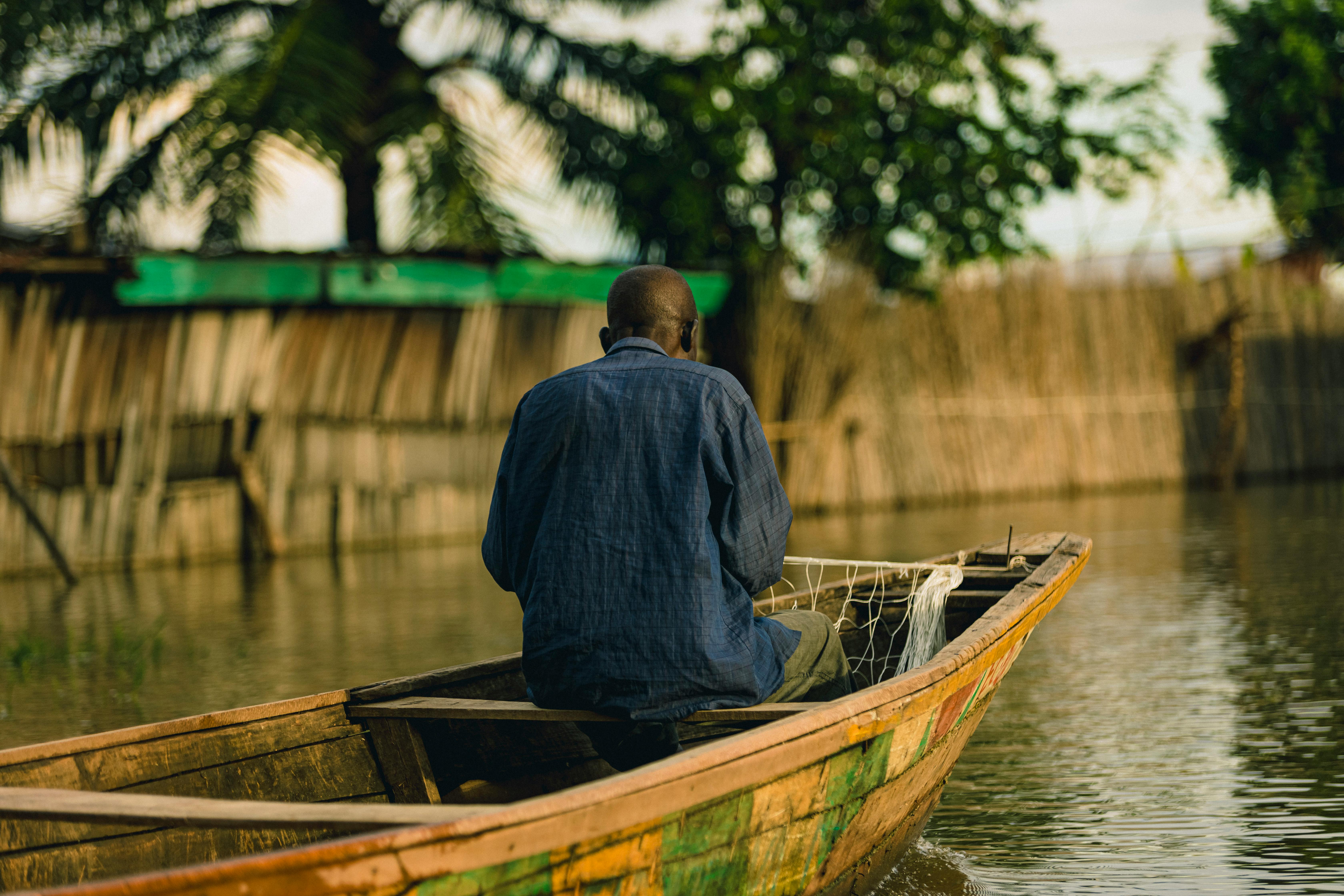 Back View of Fisherman on Boat in Village · Free Stock Photo