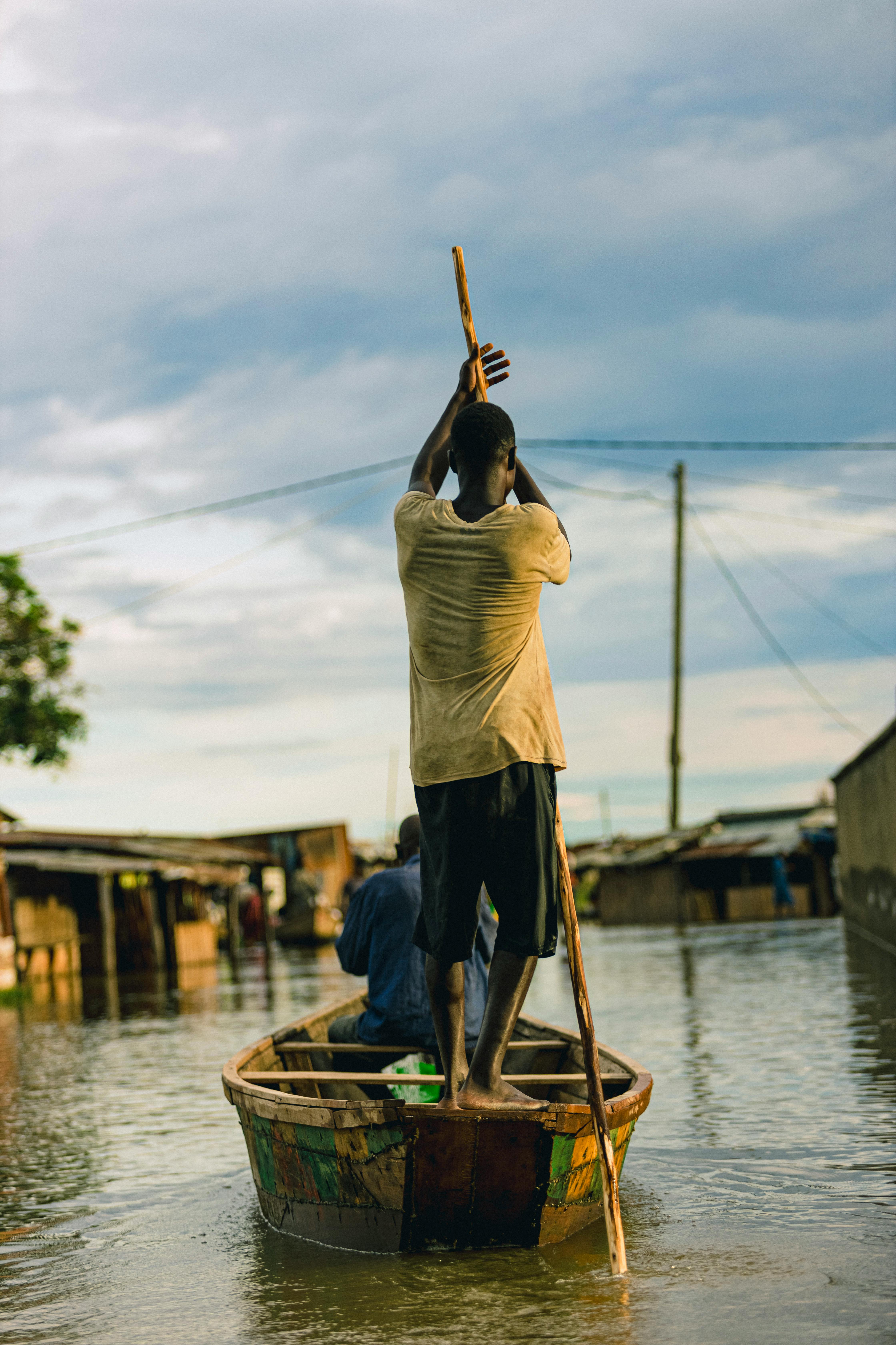 Men on Boat on Water in Village during Flood · Free Stock Photo