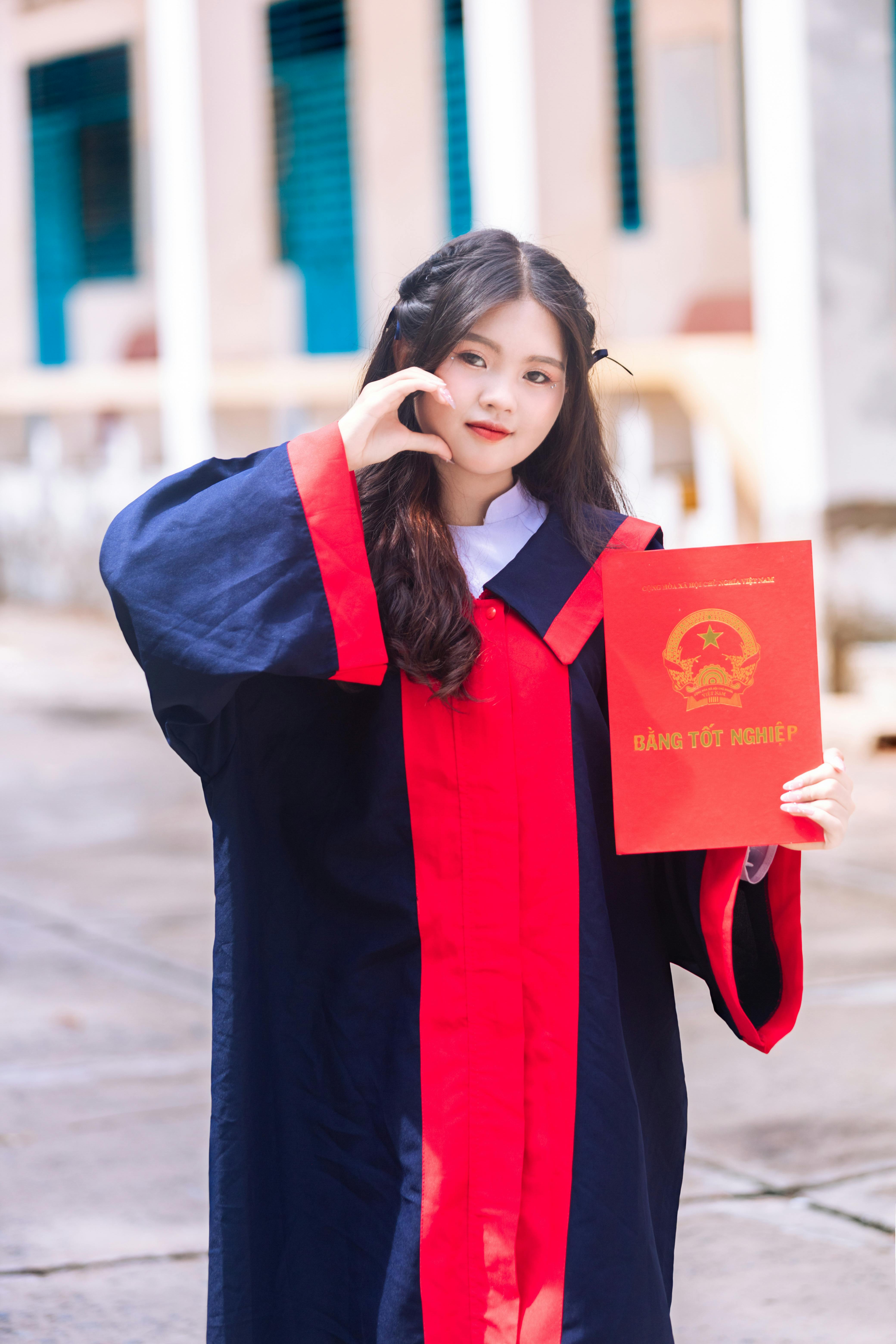 Portrait of Woman Standing and Making Heart Gesture in Graduation Gown ...
