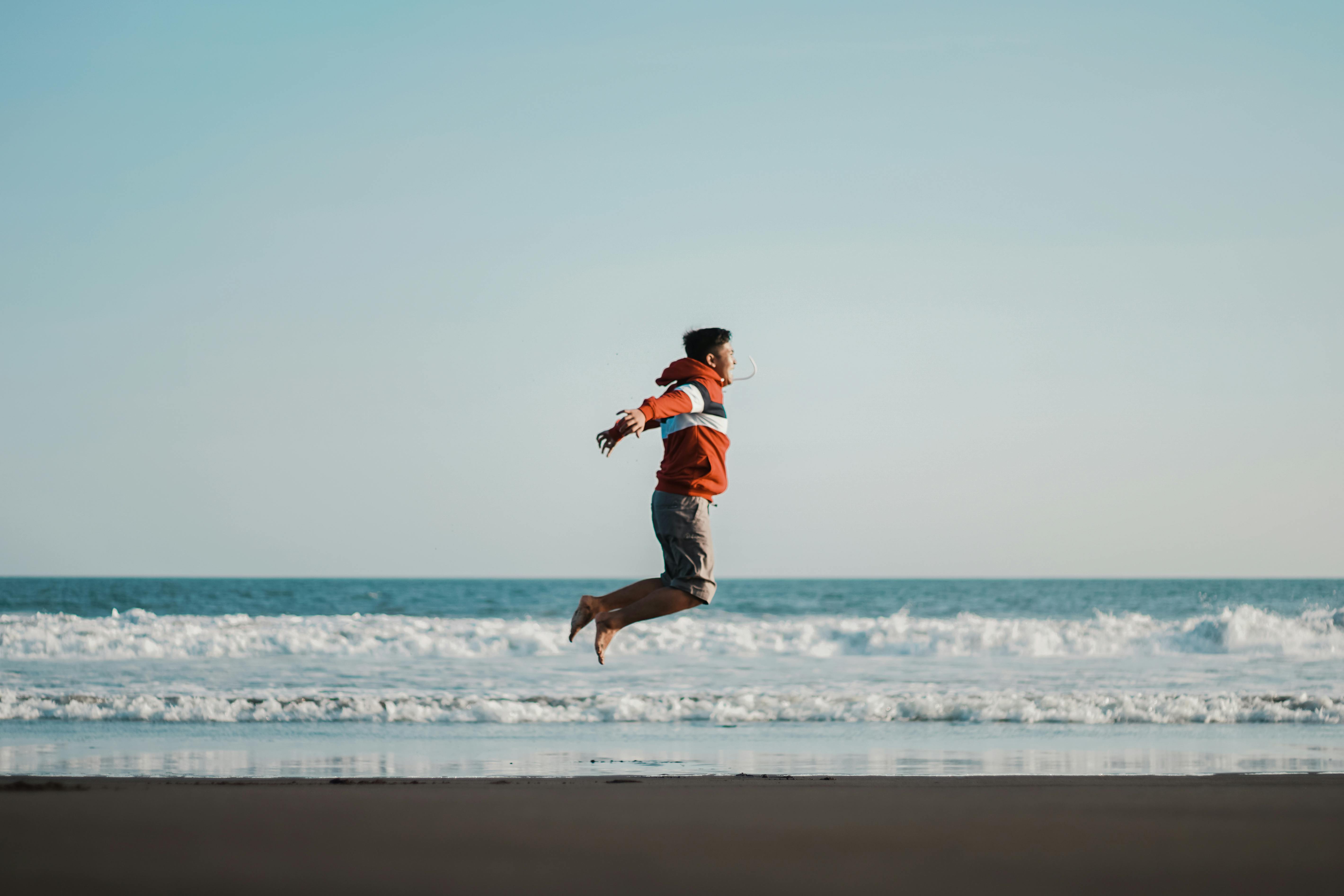 Man Jumping during Sunset on a Beach · Free Stock Photo
