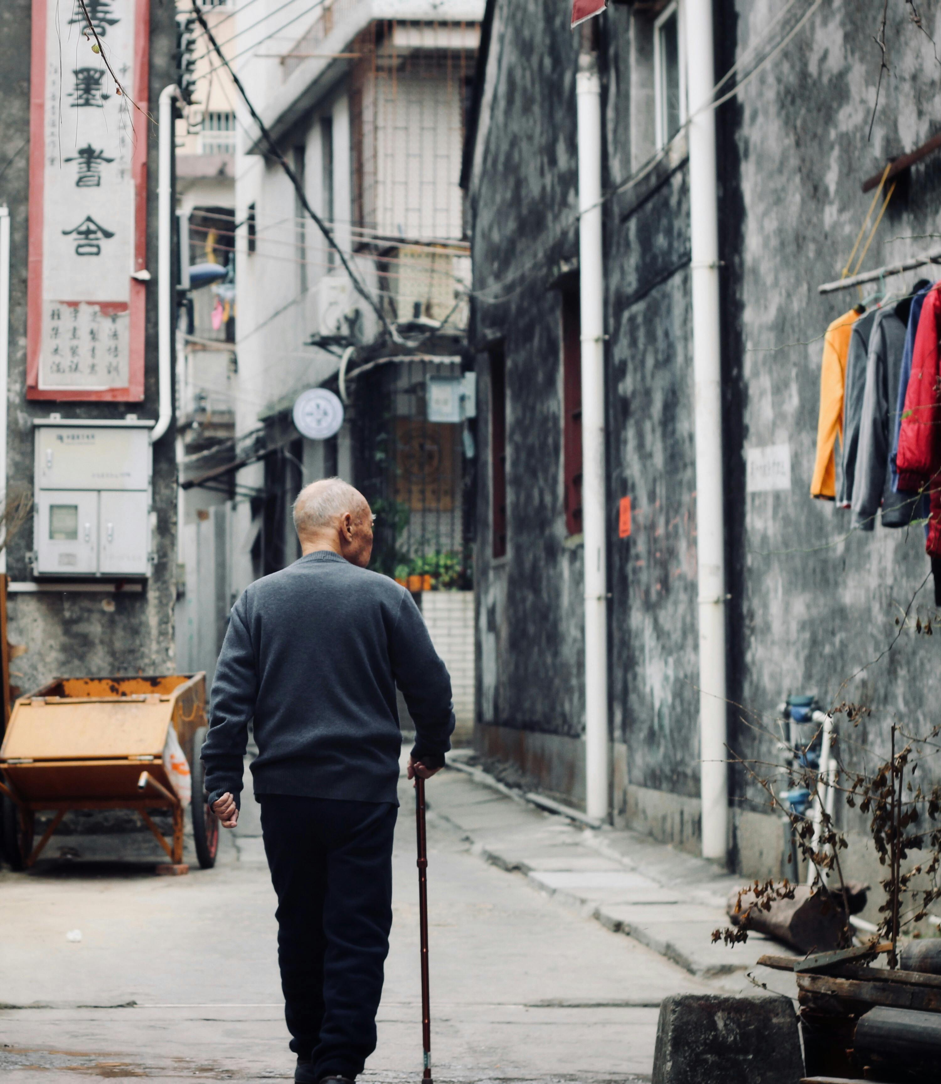 Photo of an elderly man walking on an alley · Free Stock Photo