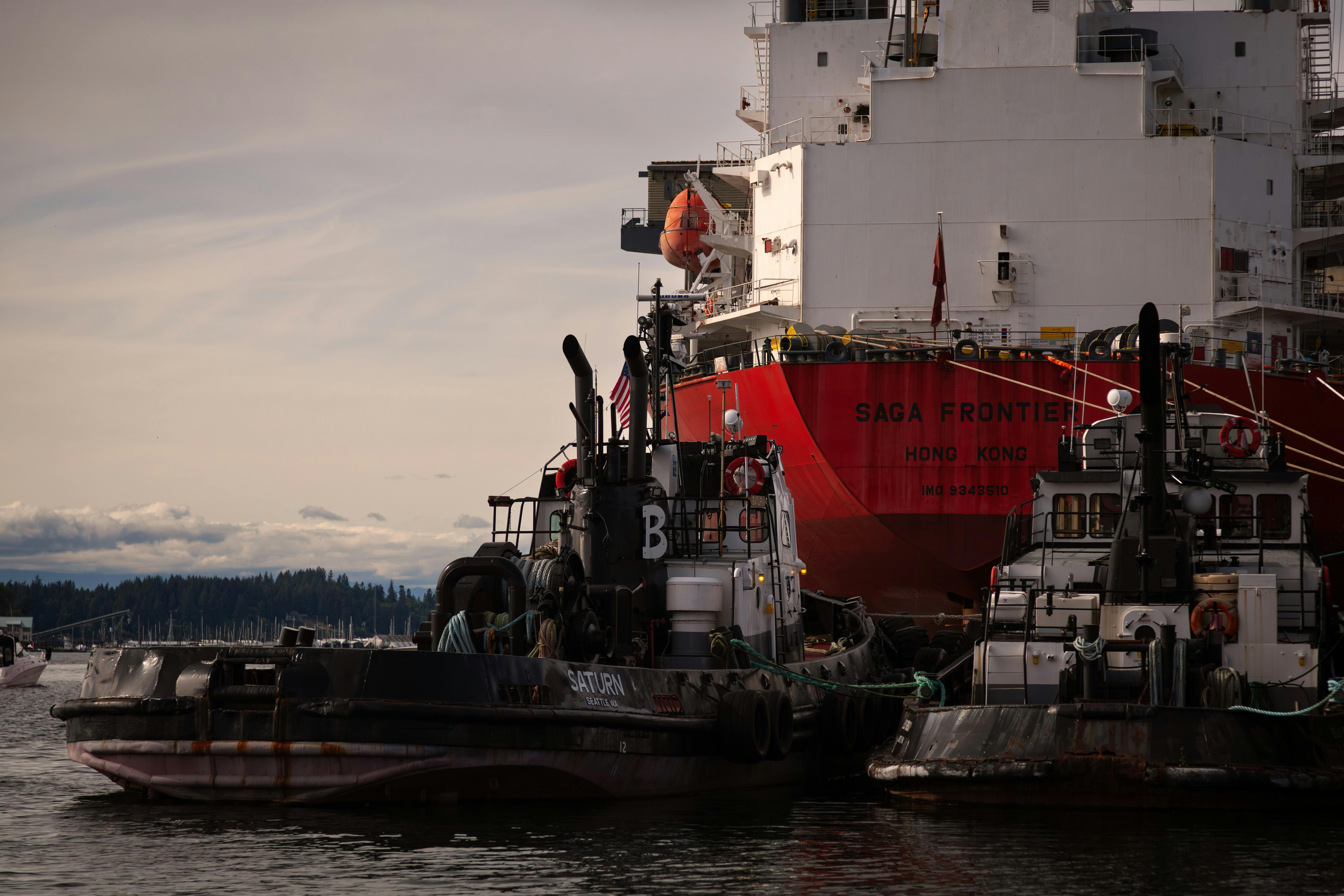 Tugboats Behind the Cargo Ship Saga Frontier · Free Stock Photo