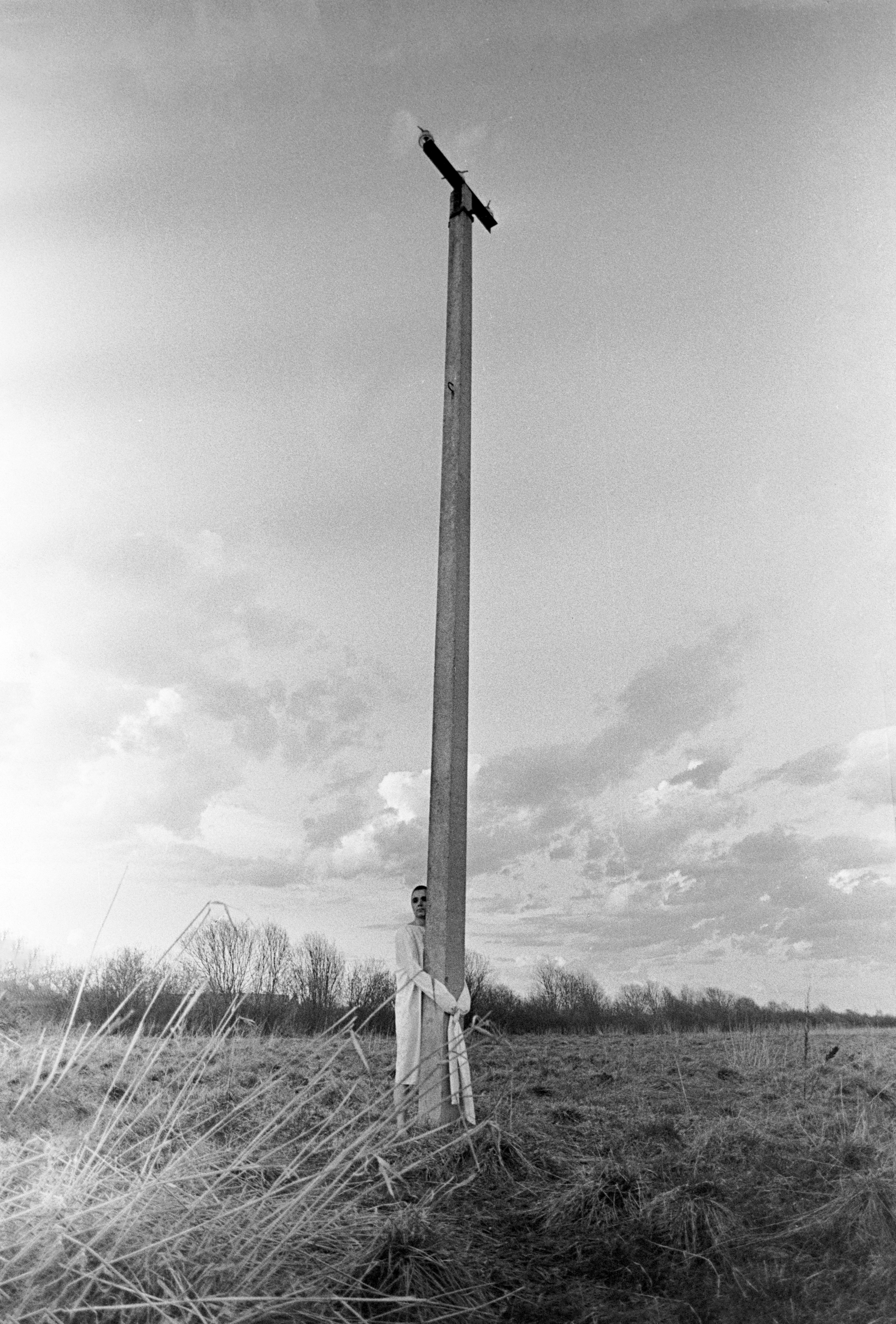 Black and White Photo of a Man Hugging a Concrete Pole on a Field ...