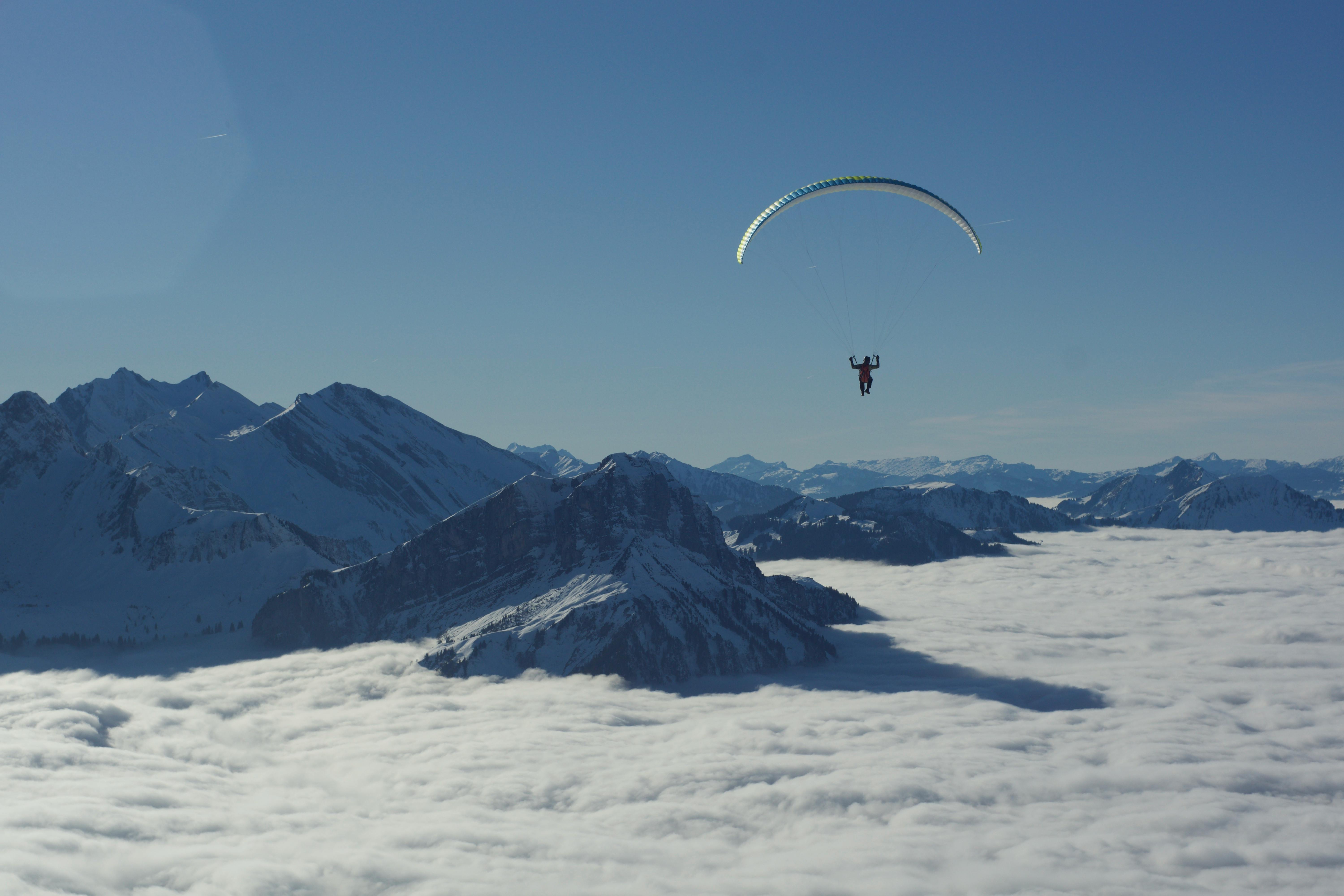 Person Parachuting over Cloud and Mountains Peaks · Free Stock Photo
