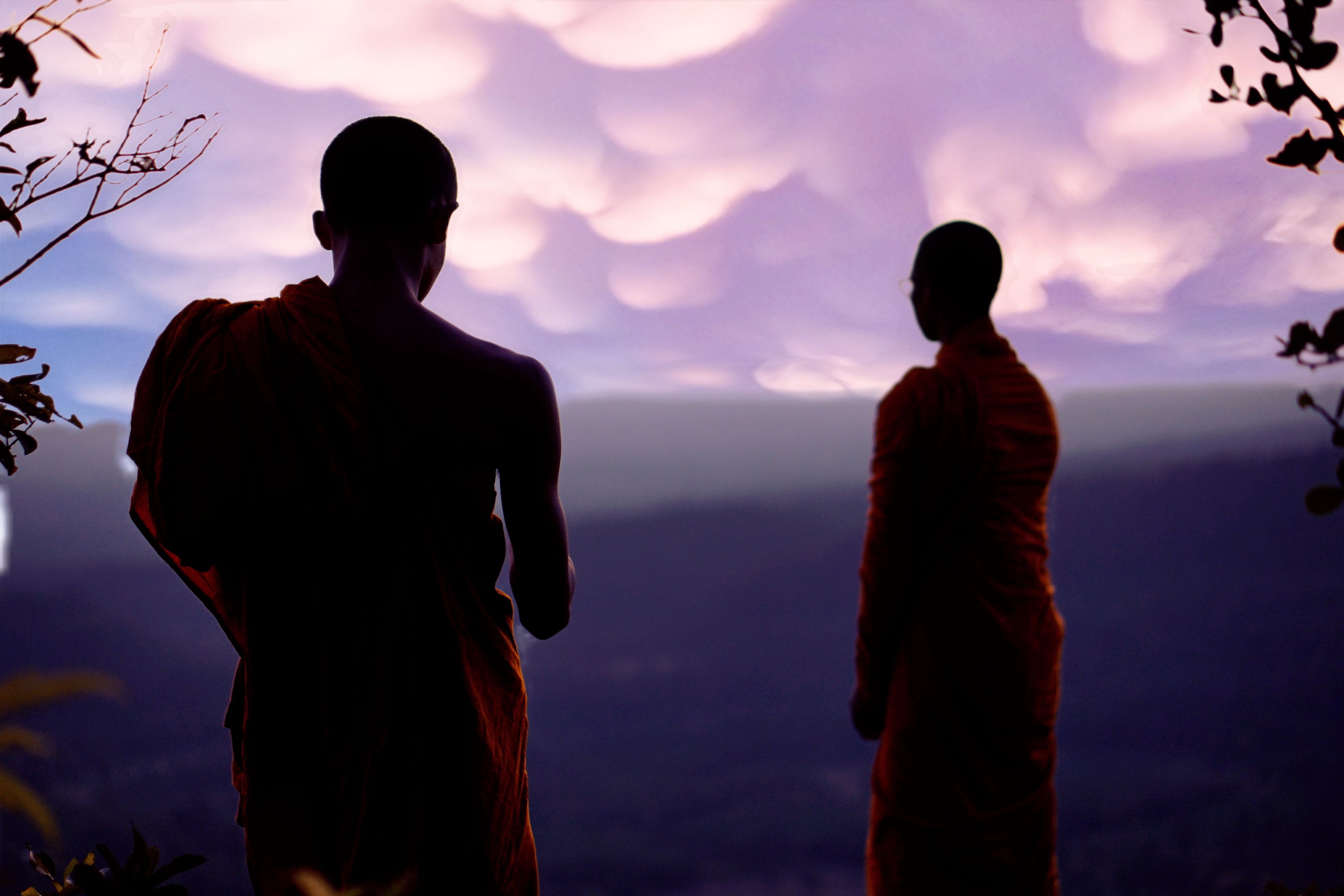 Two buddhist monks standing in front of a mountain with clouds in the ...