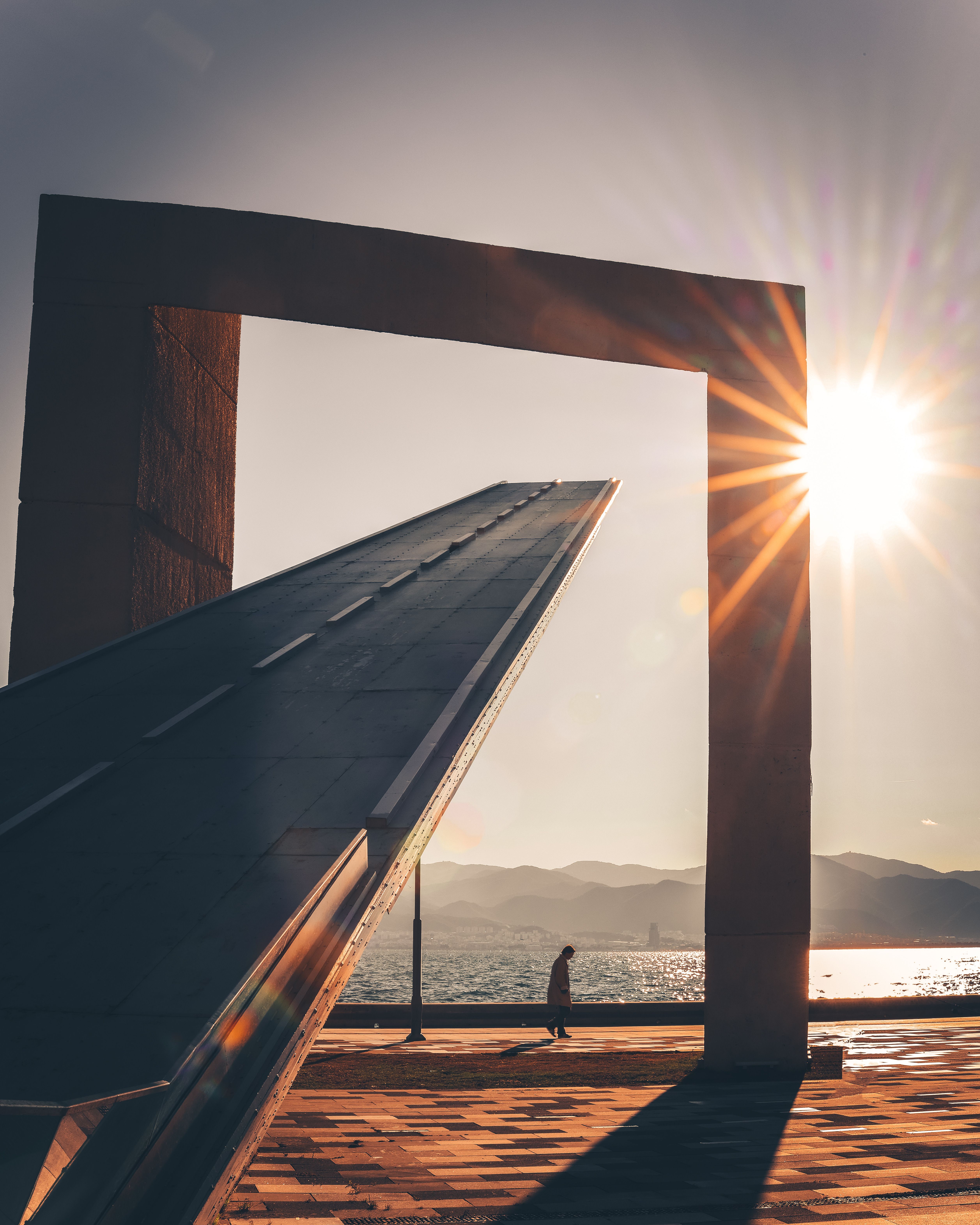 A man walking through a large arch with the sun behind him · Free Stock ...