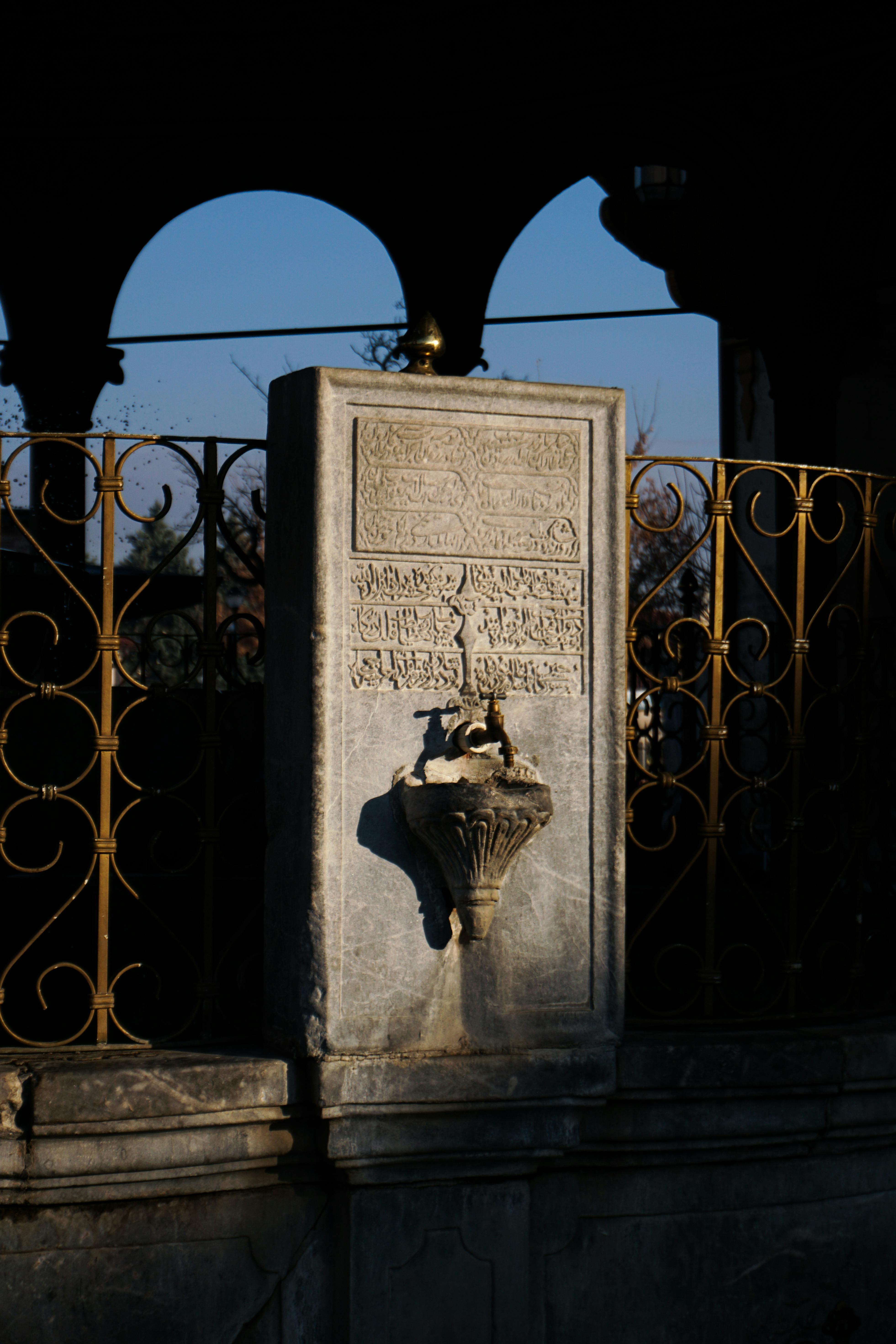 A water fountain with a metal railing and iron gate · Free Stock Photo