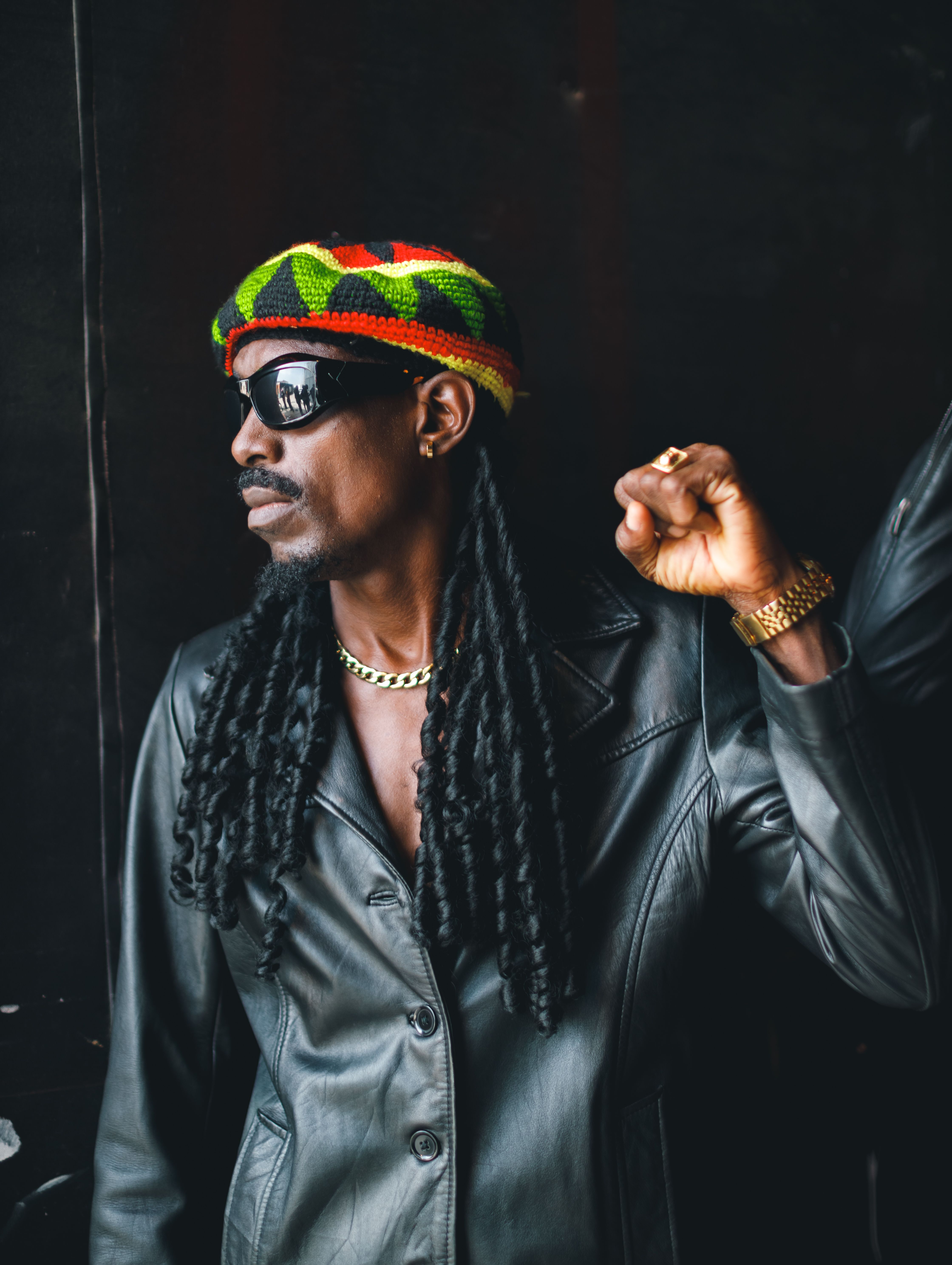 A man with dreadlocks and sunglasses is wearing a hat · Free Stock Photo