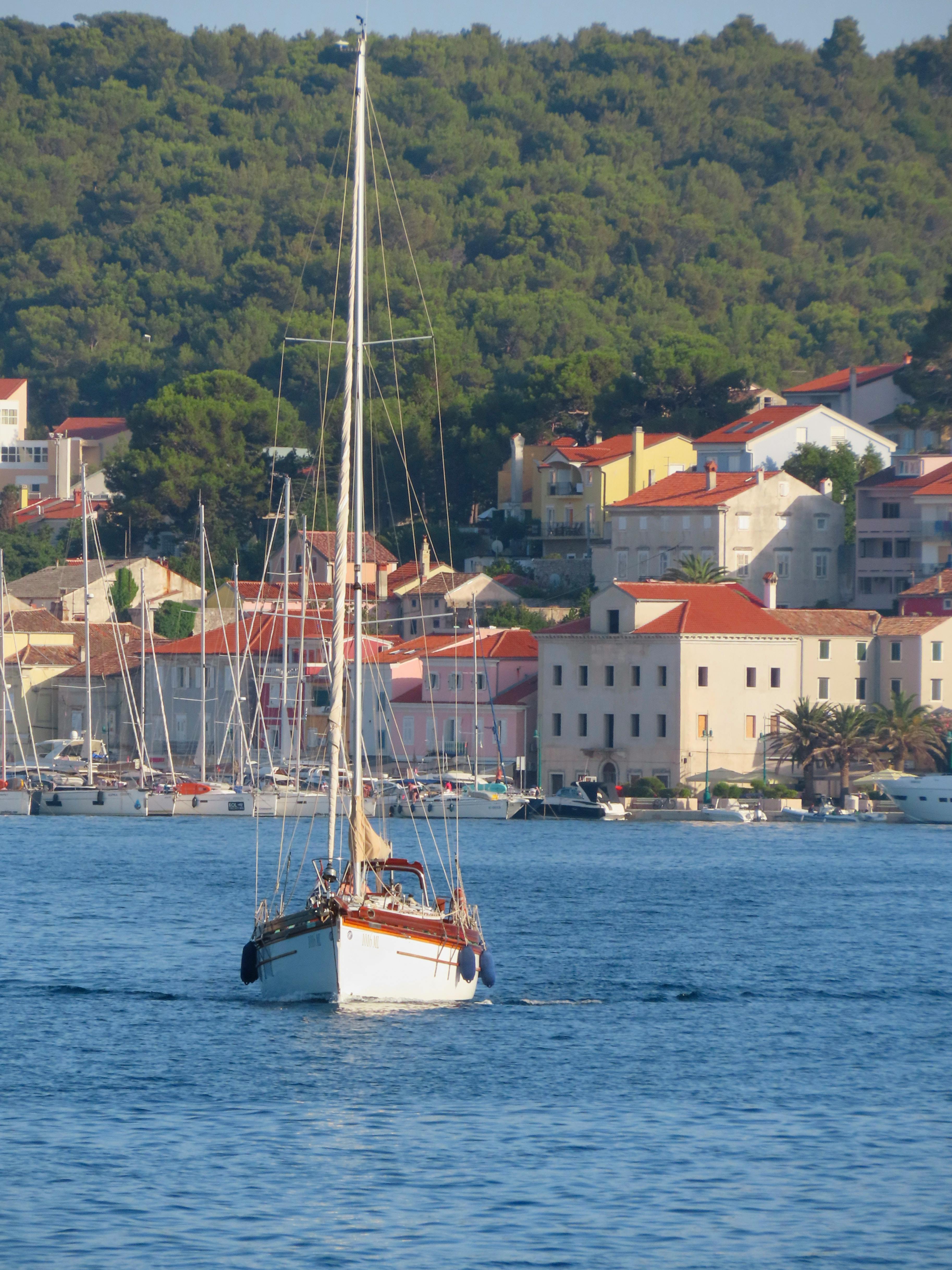 Sailboat against Coastal Houses · Free Stock Photo