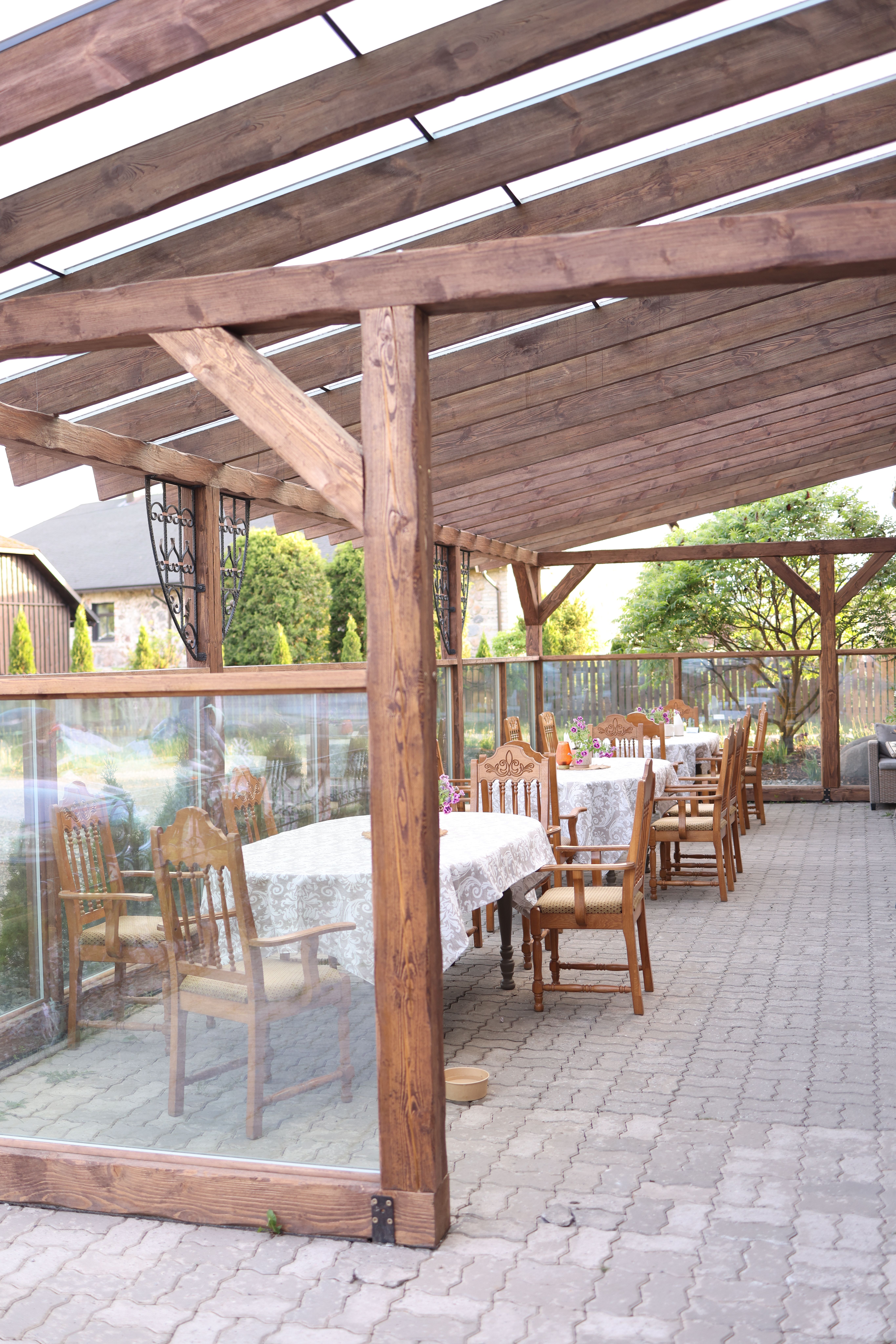 A patio with tables and chairs under a wooden roof · Free Stock Photo