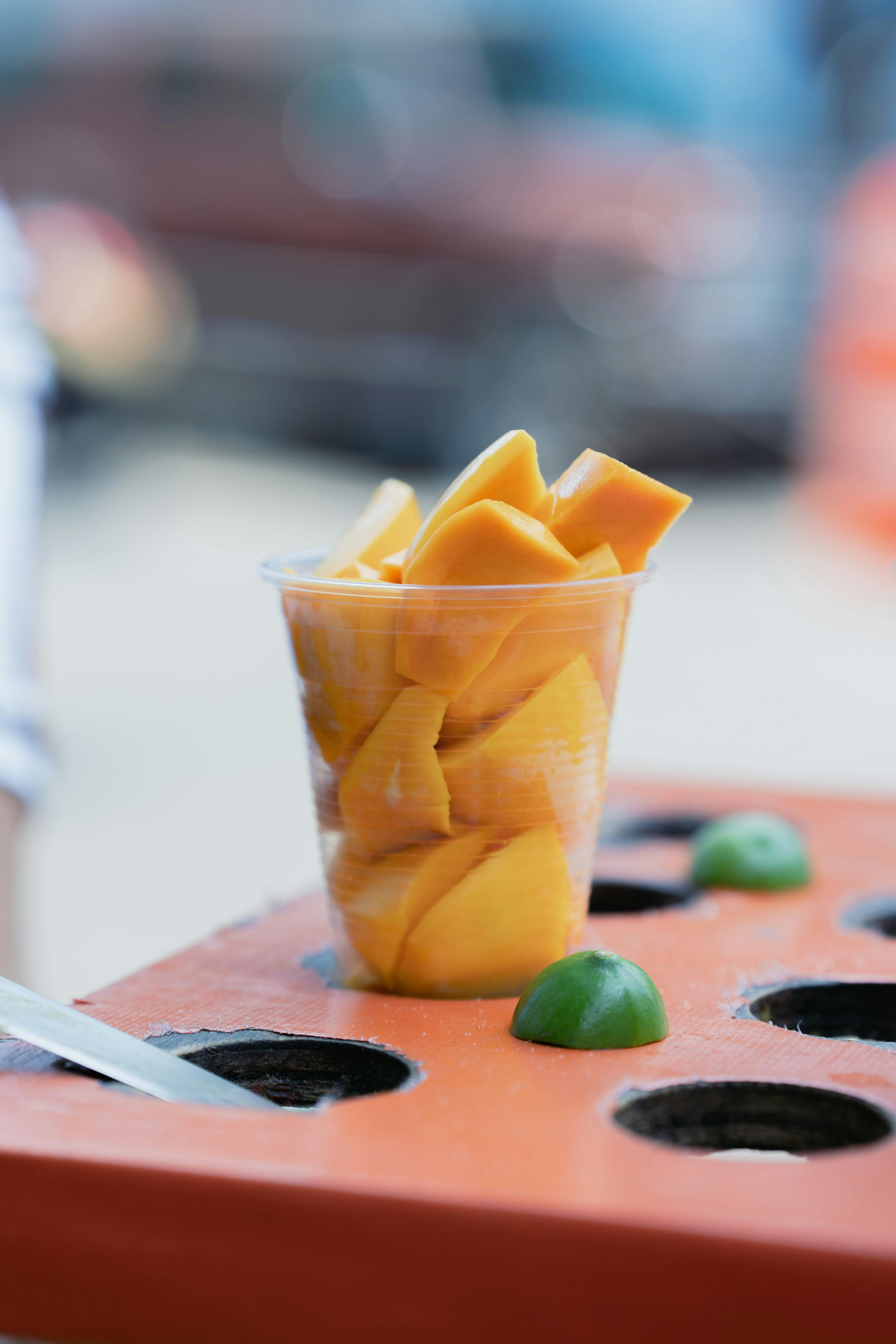 A cup of mangoes sitting on top of a table · Free Stock Photo