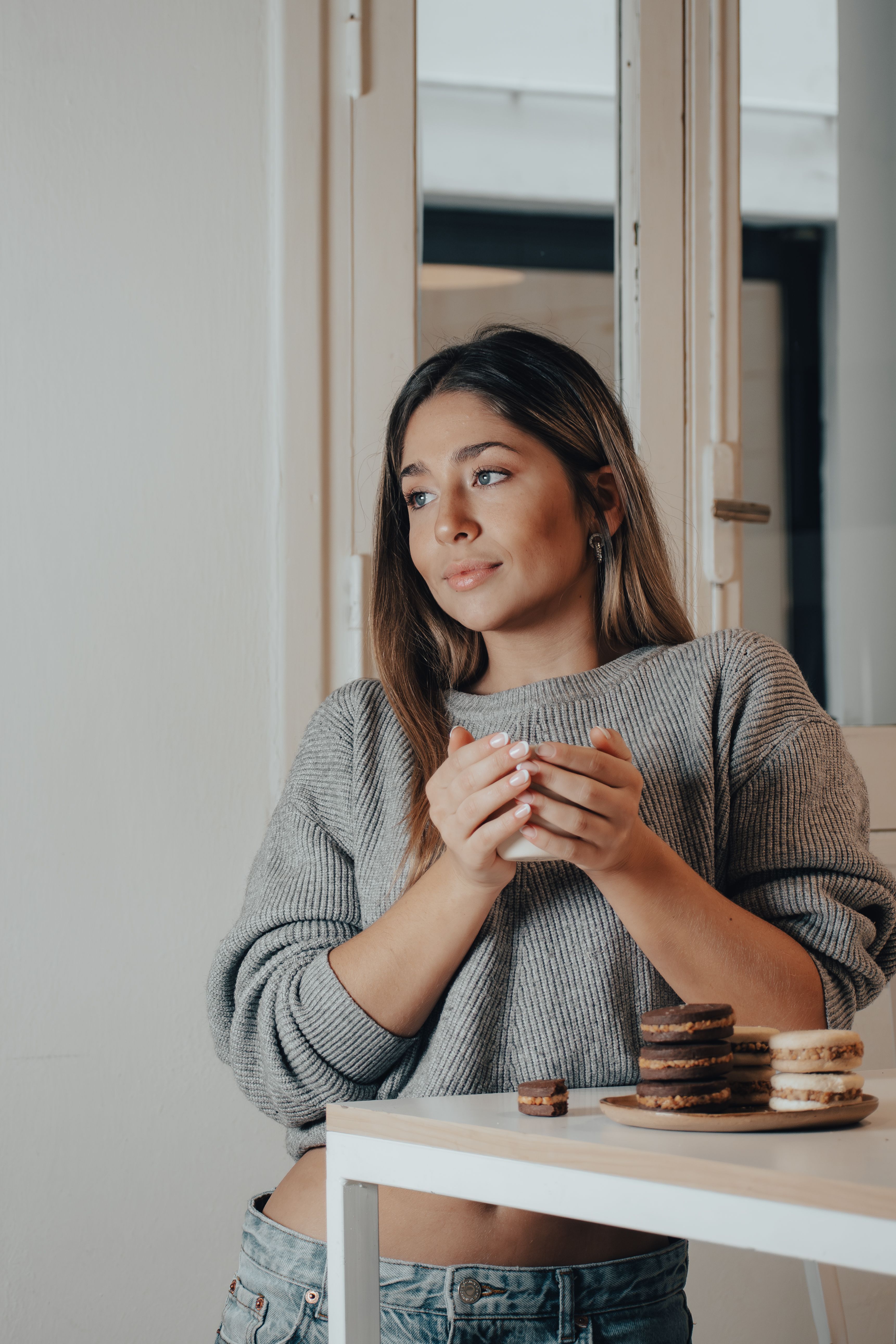 Woman Standing next to Table with Cookies Holding Mug · Free Stock Photo