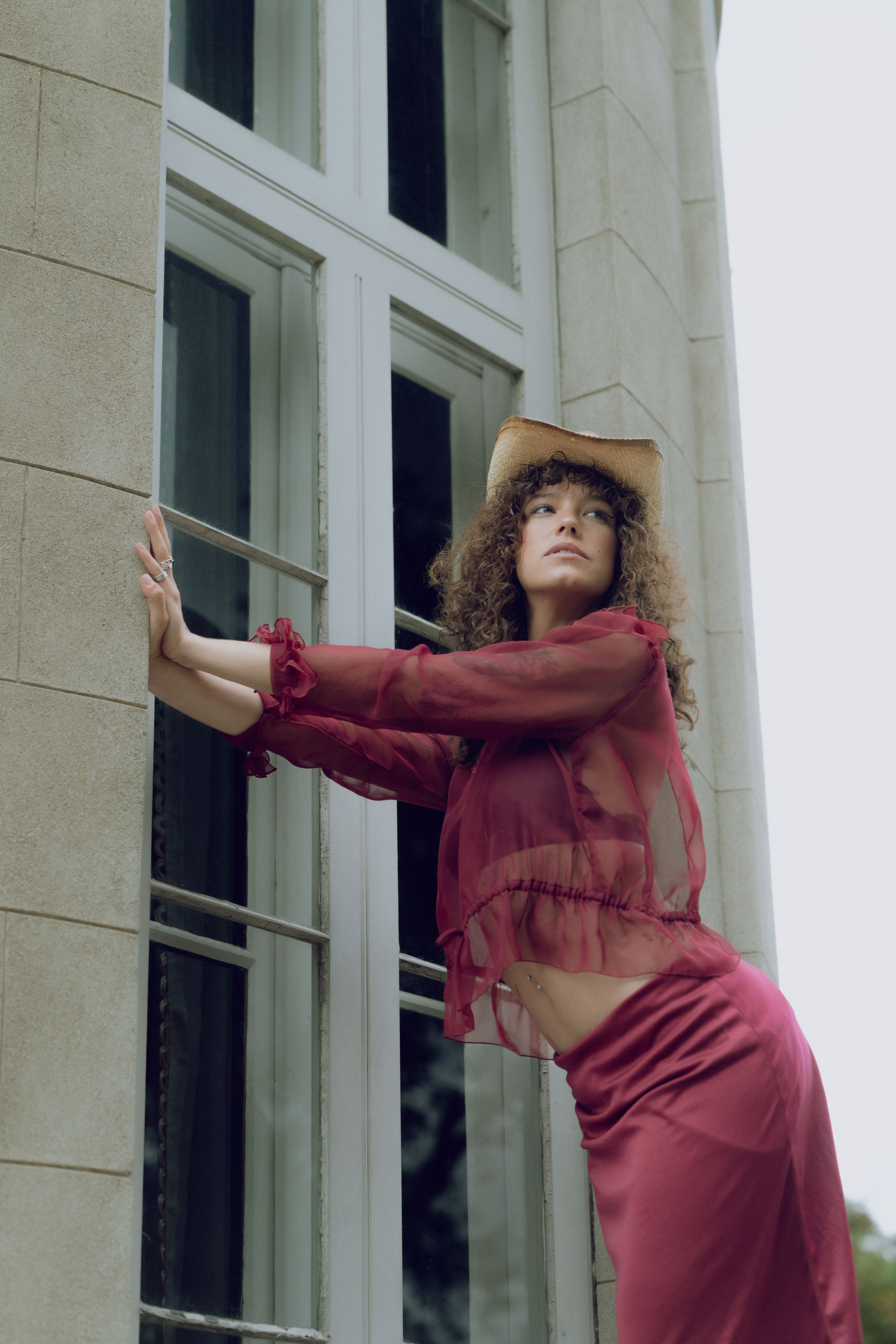 A woman in a red dress leaning against a window · Free Stock Photo