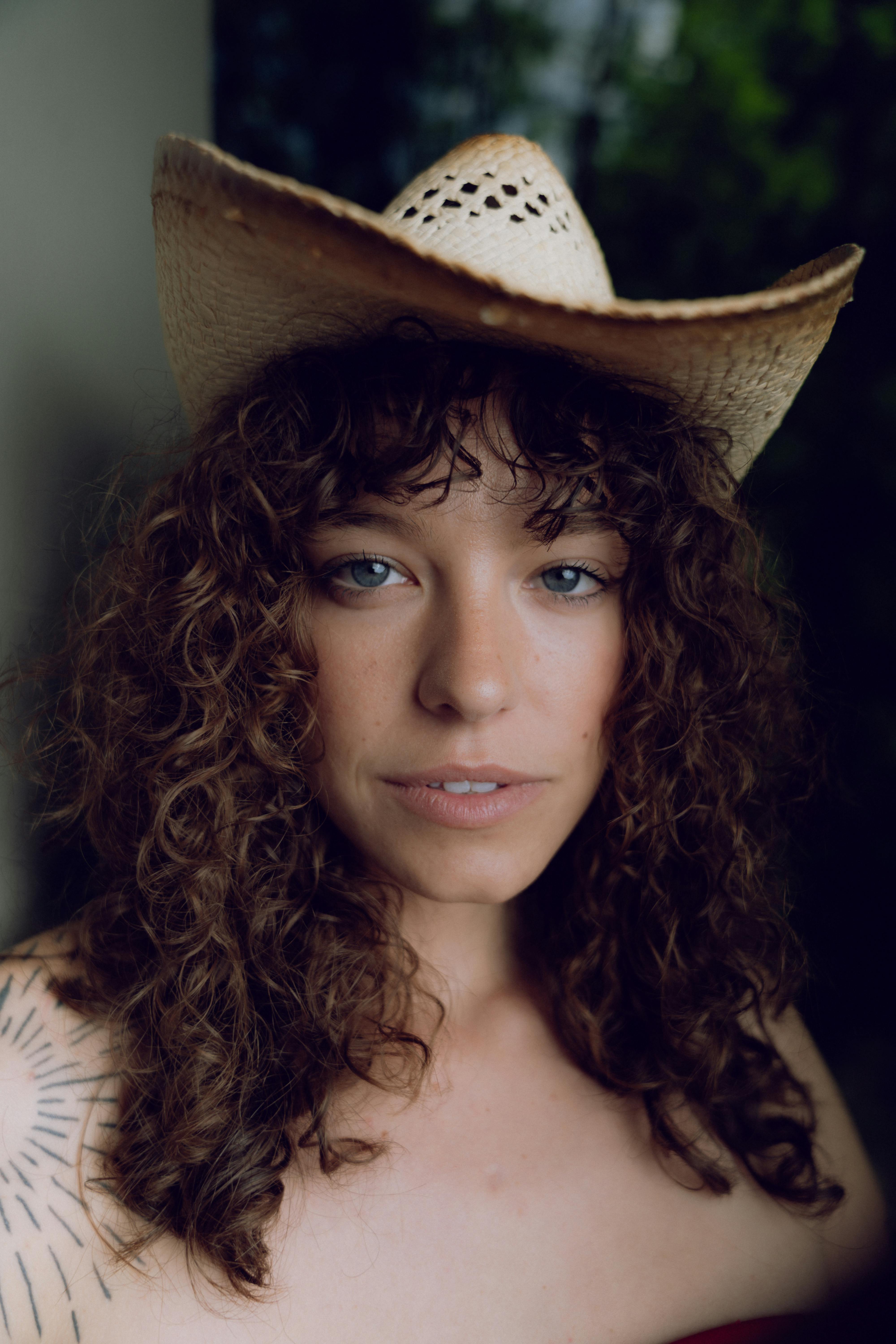 A woman with curly hair wearing a cowboy hat · Free Stock Photo