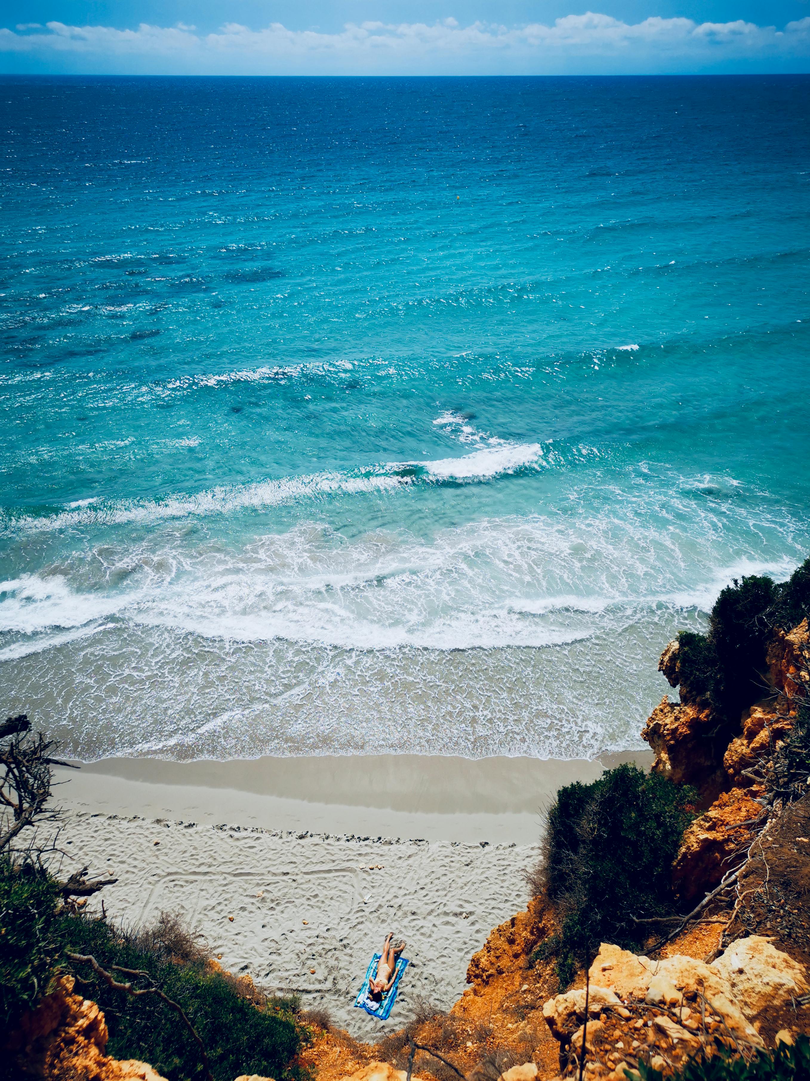 A person embracing the sun in Menorca, Spain. · Free Stock Photo