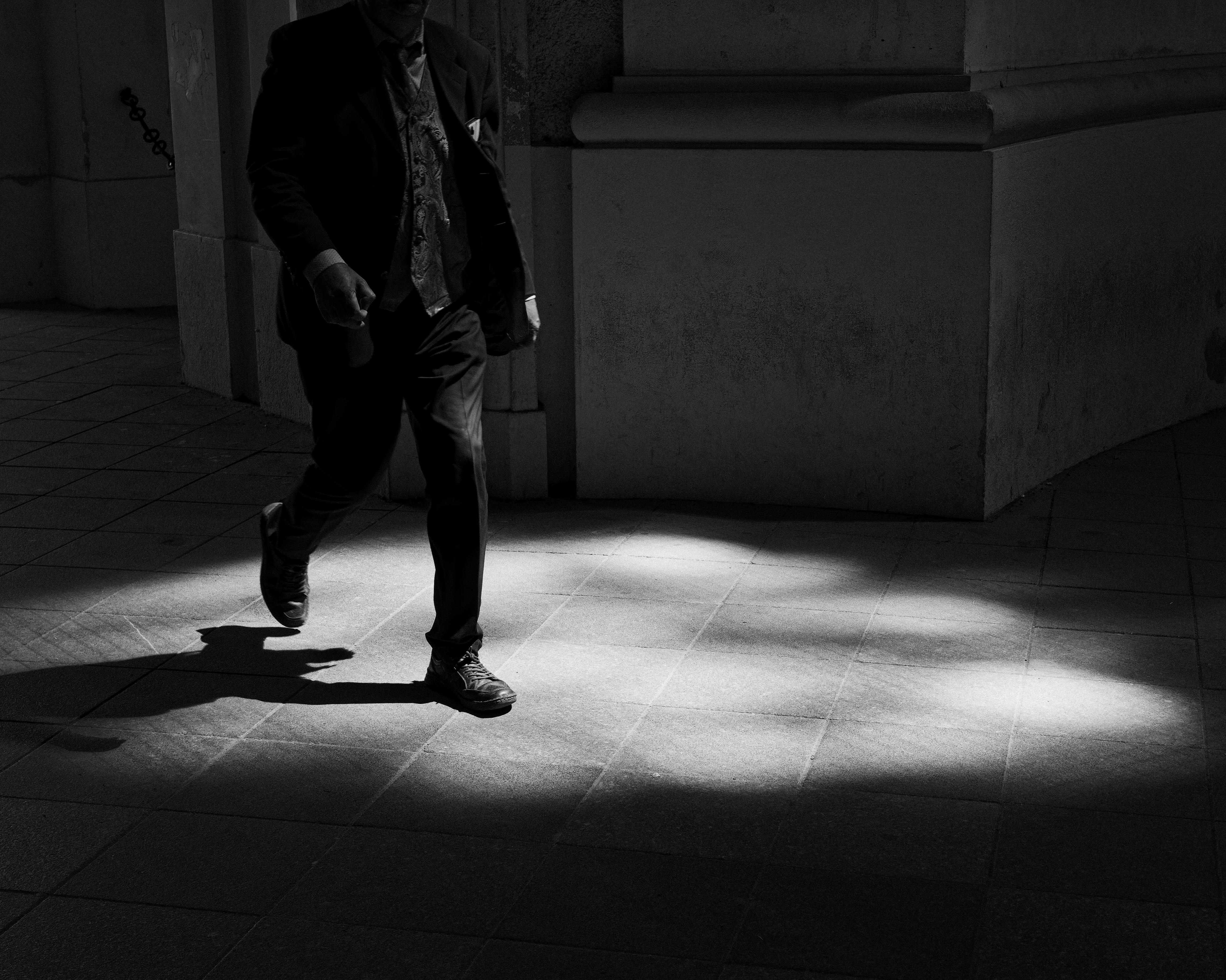 A man walking in the shadows of a building · Free Stock Photo