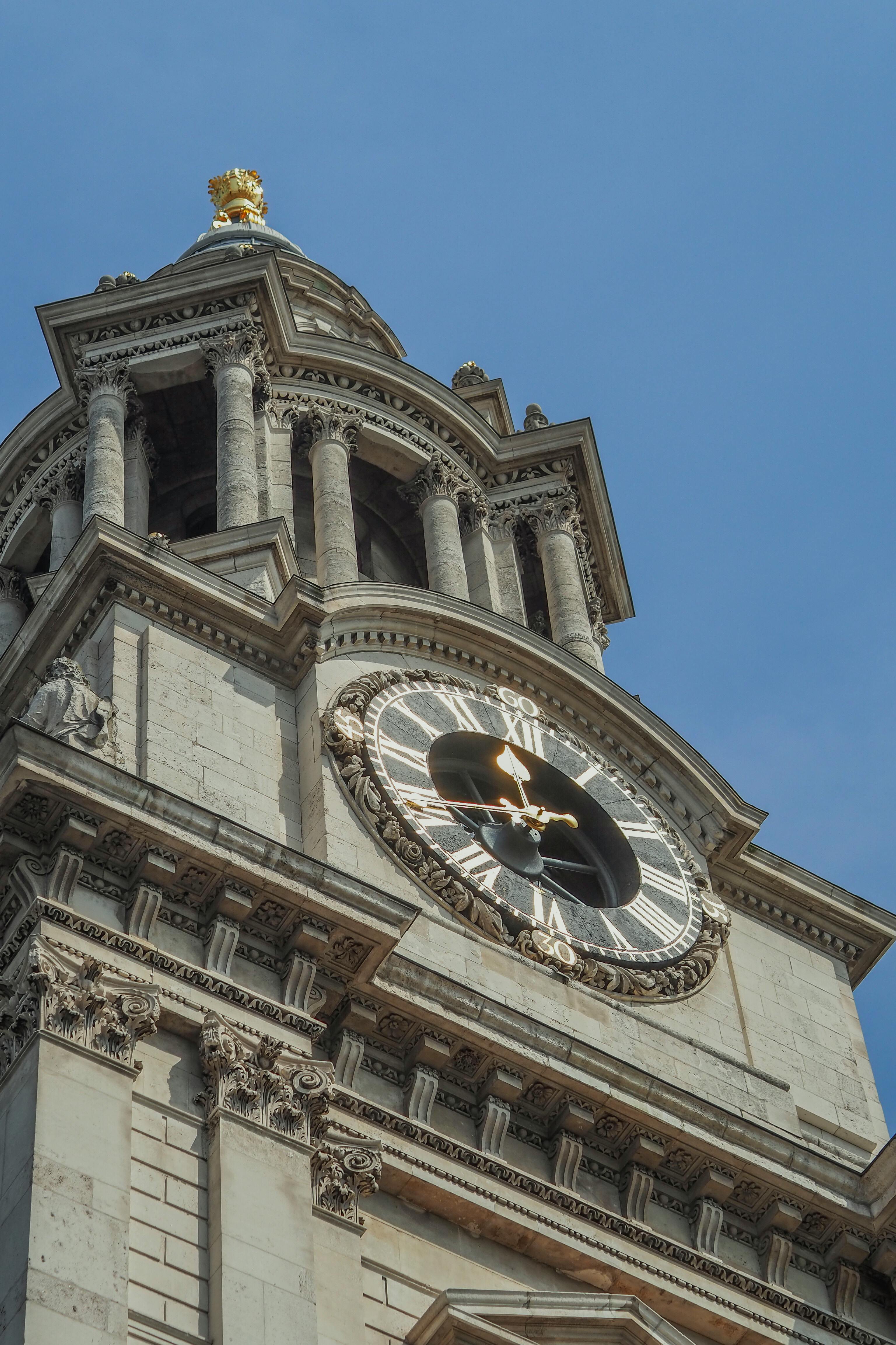 A close up of a clock tower with a blue sky · Free Stock Photo