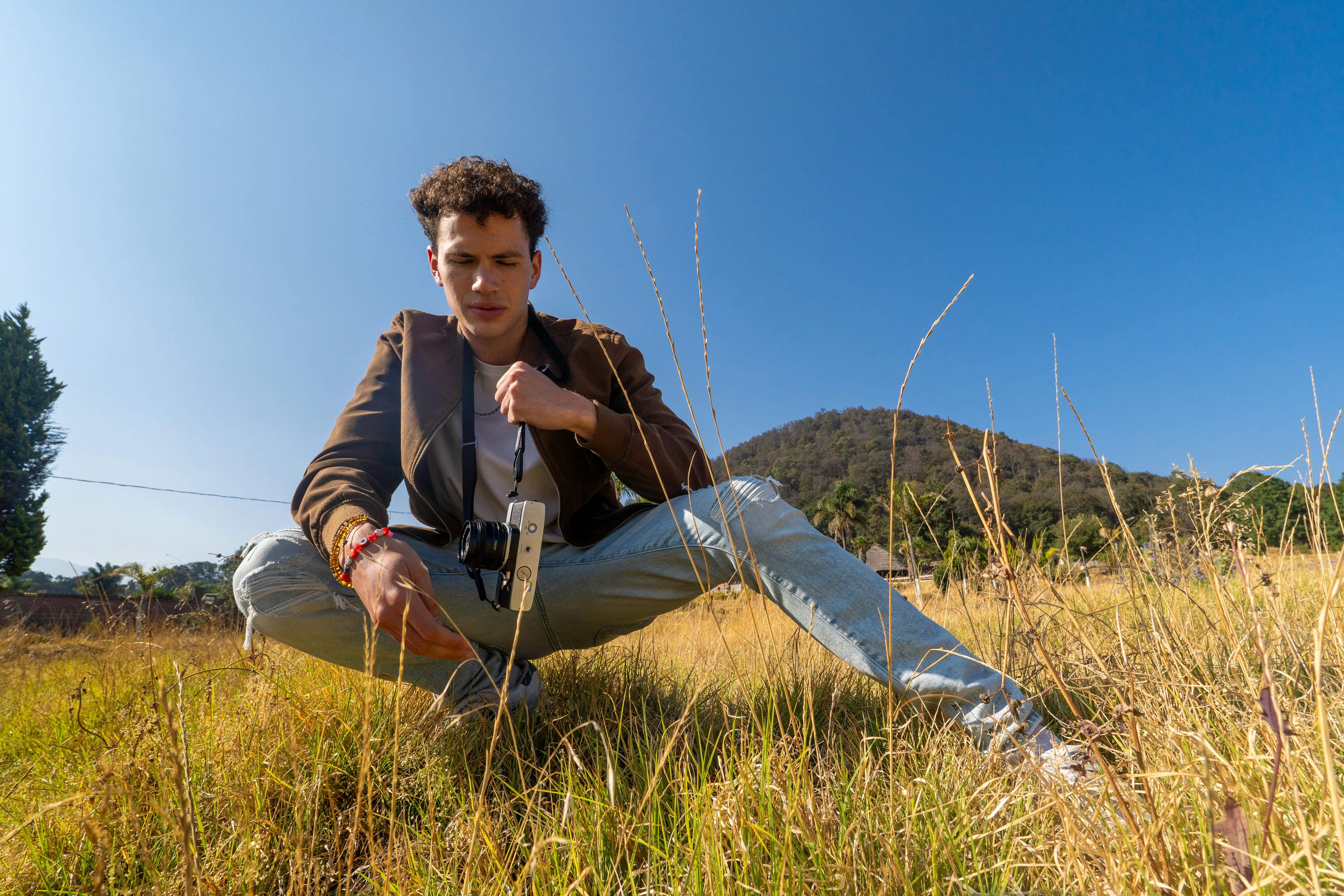 Photographer Crouching and Looking at a Camera in his Hand · Free Stock ...