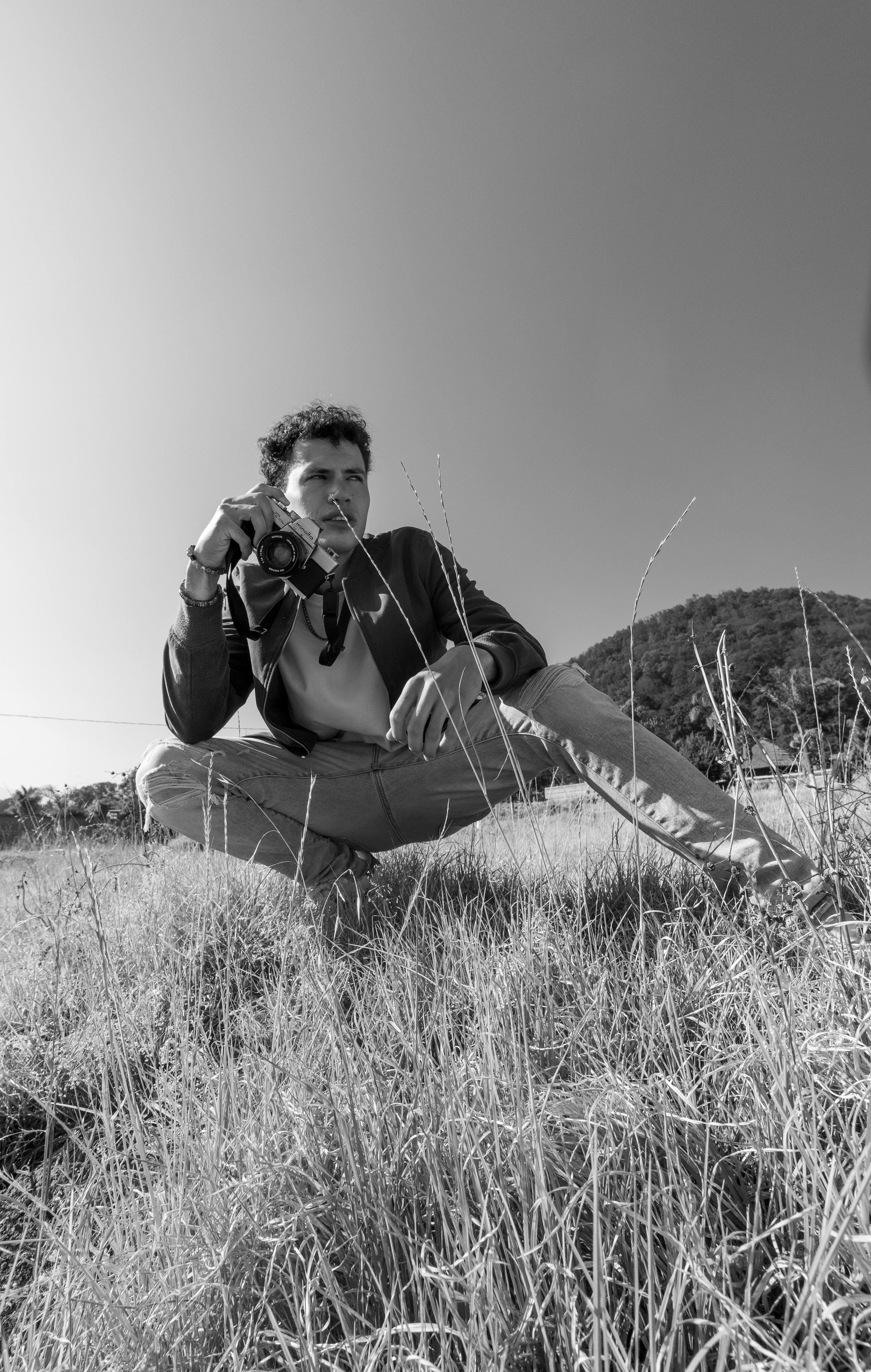 Photographer Crouching in a Field with a Camera in his Hand · Free ...