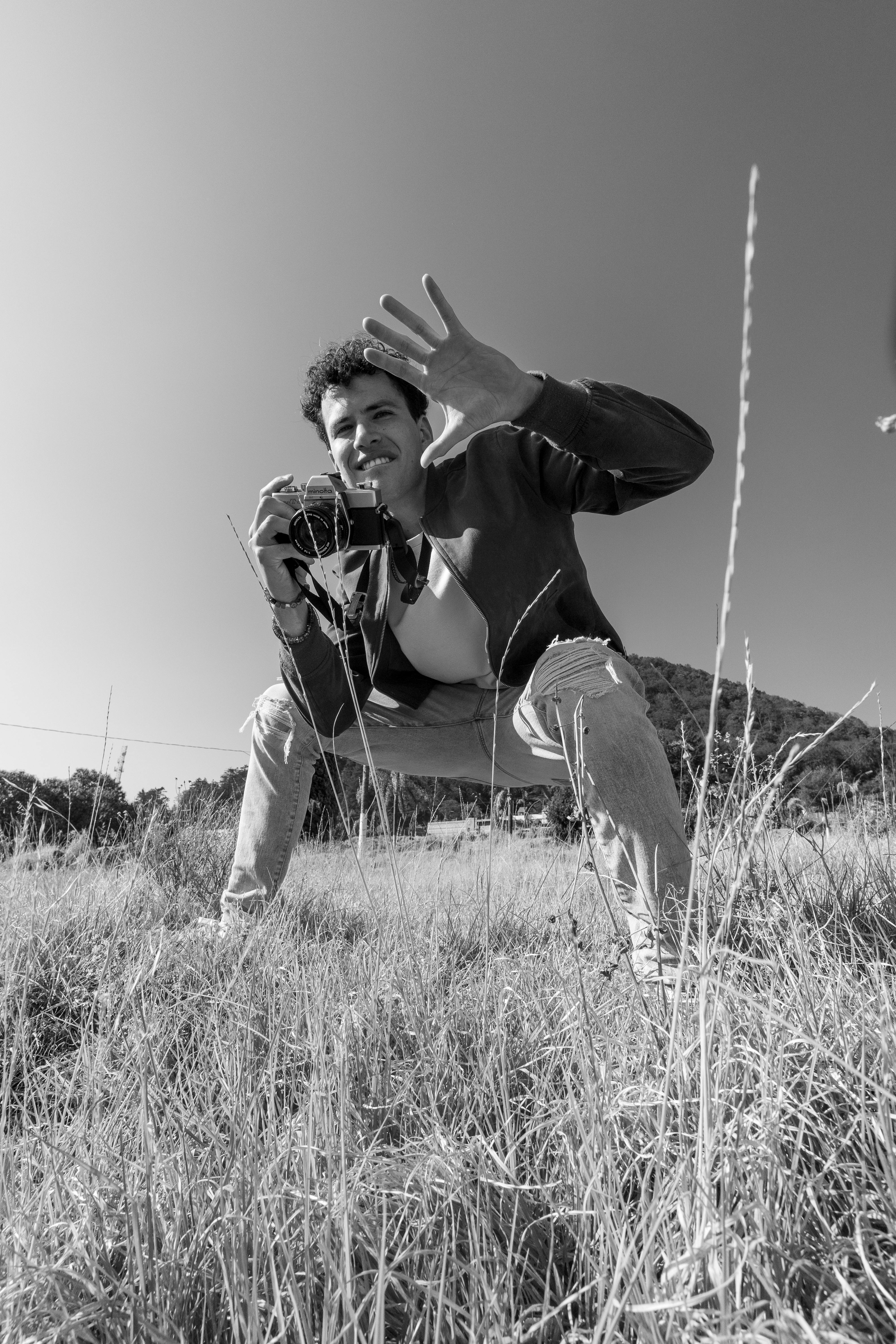 Photographer Crouching with a Camera in his Hand and Waving · Free ...