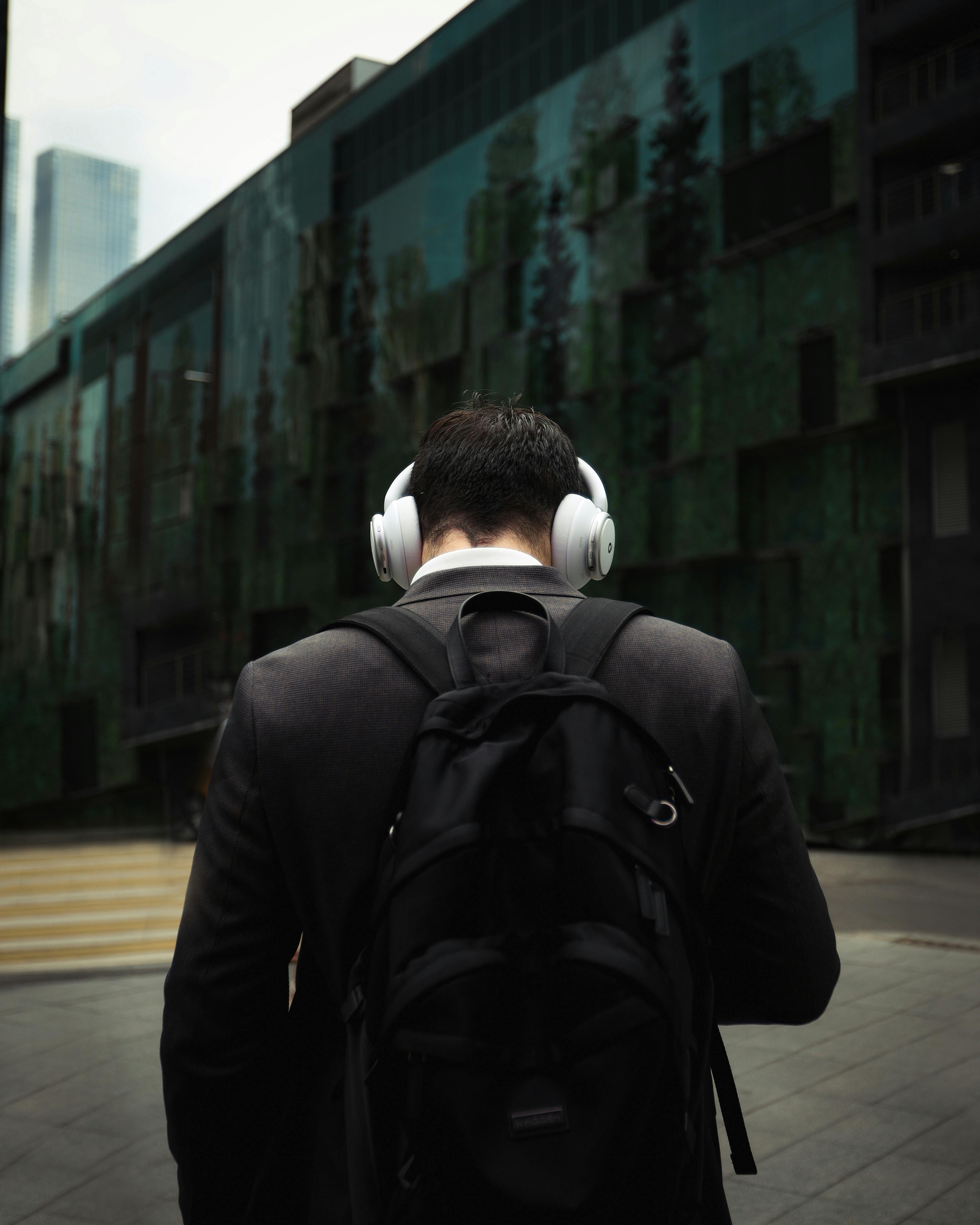 A man with headphones walking down a street · Free Stock Photo