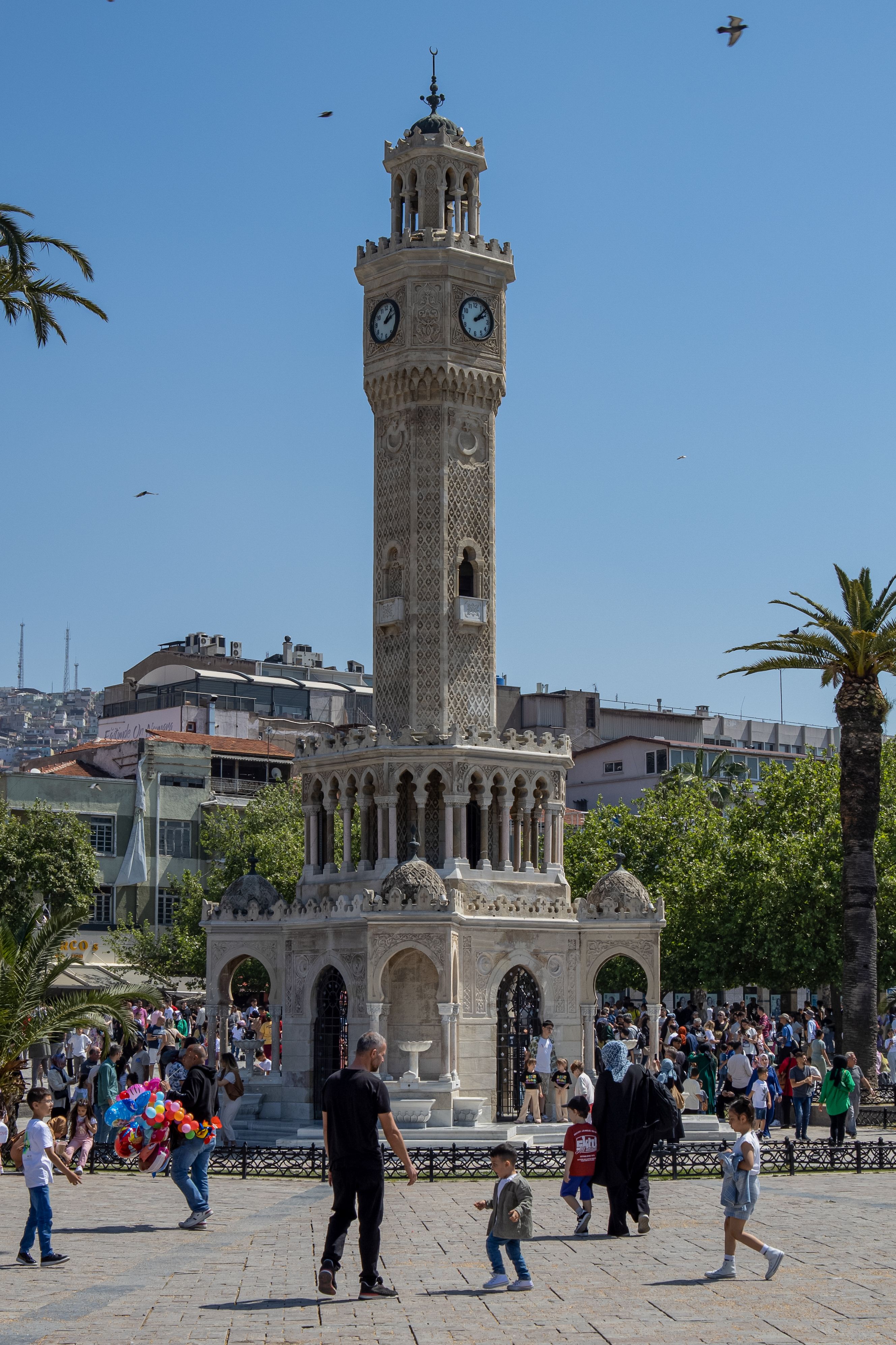 A clock tower in a plaza with people walking around · Free Stock Photo
