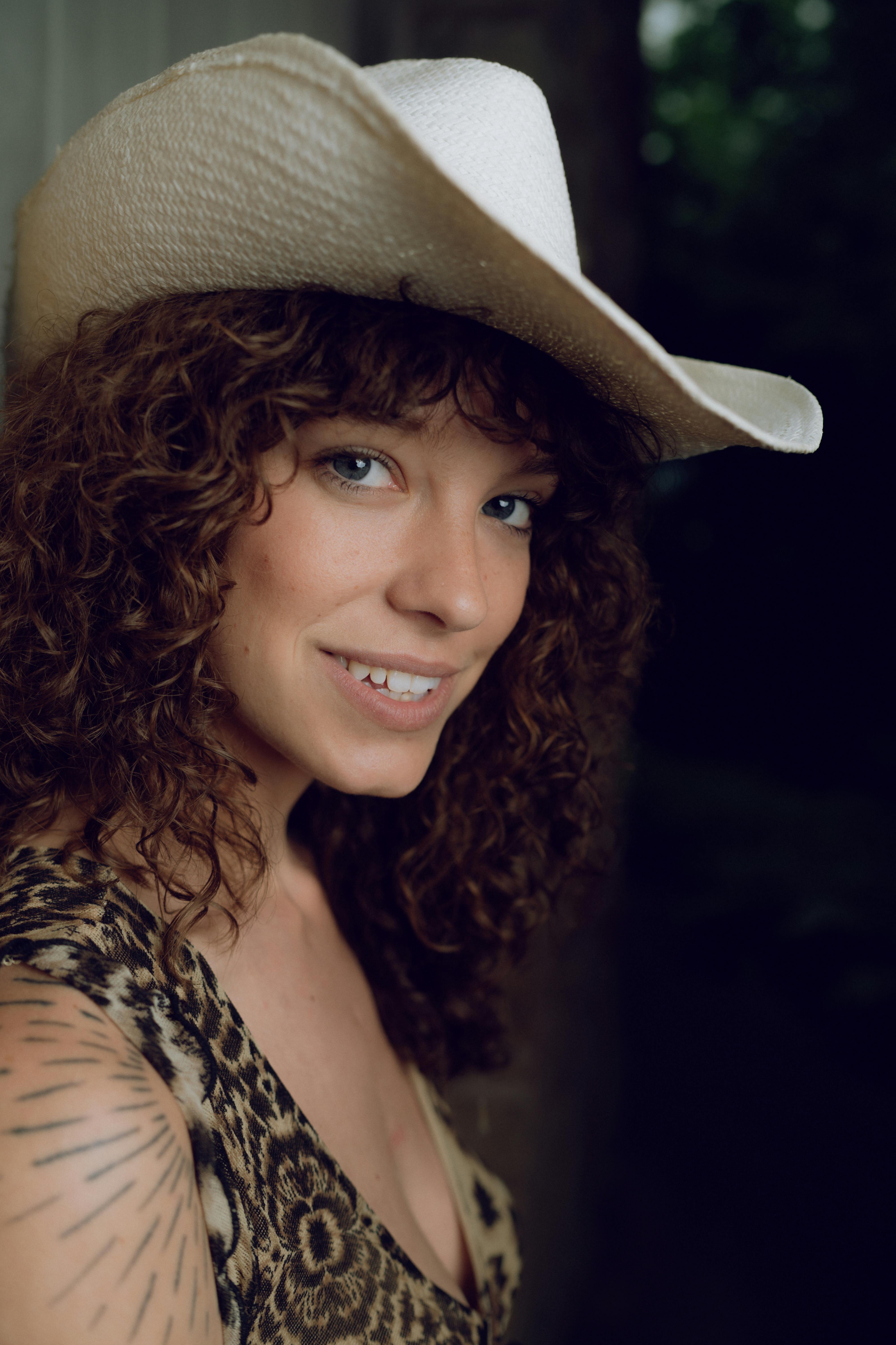 A woman with curly hair and a cowboy hat · Free Stock Photo