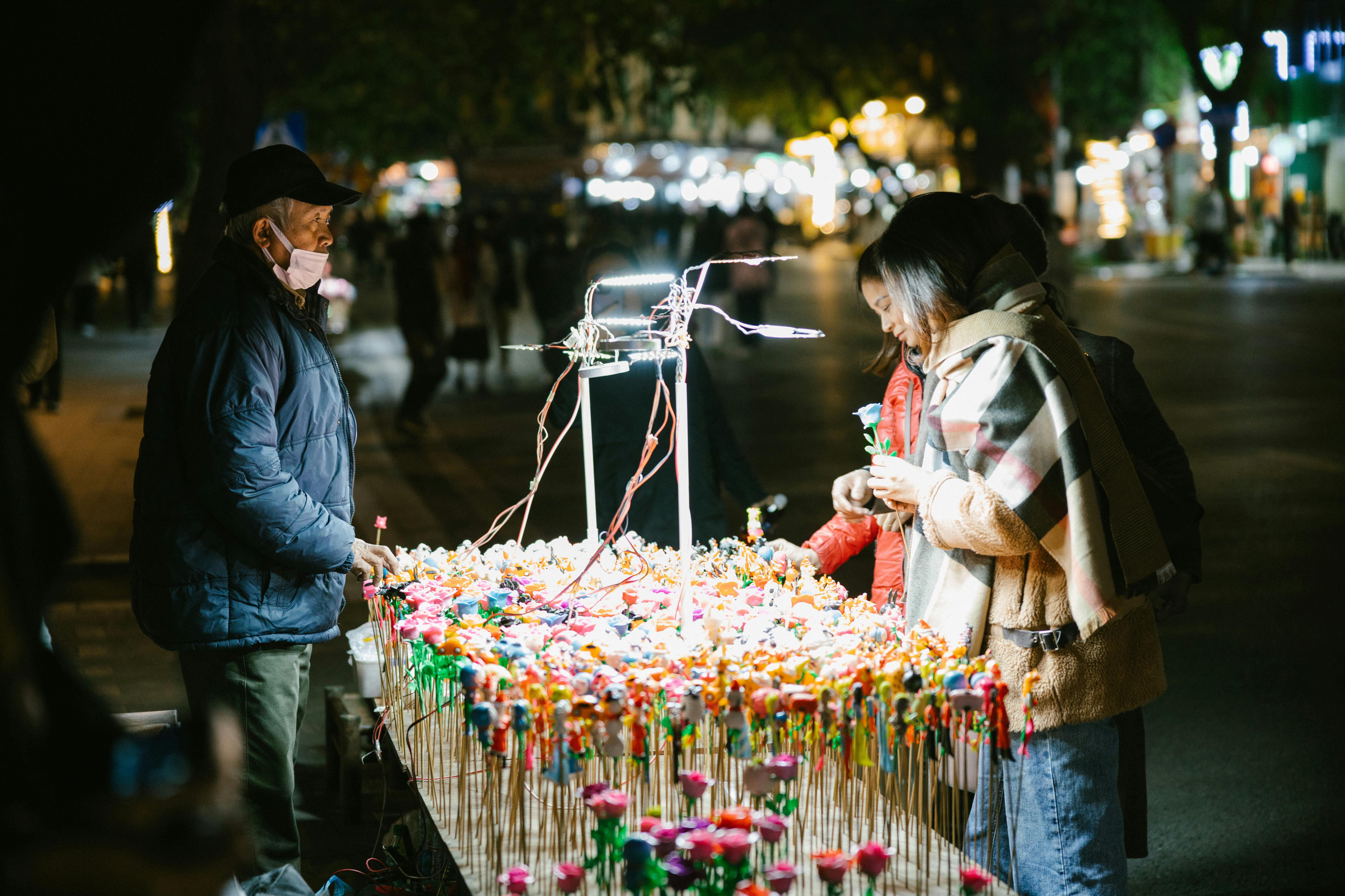 Man Selling Flowers on Sticks on a Street · Free Stock Photo